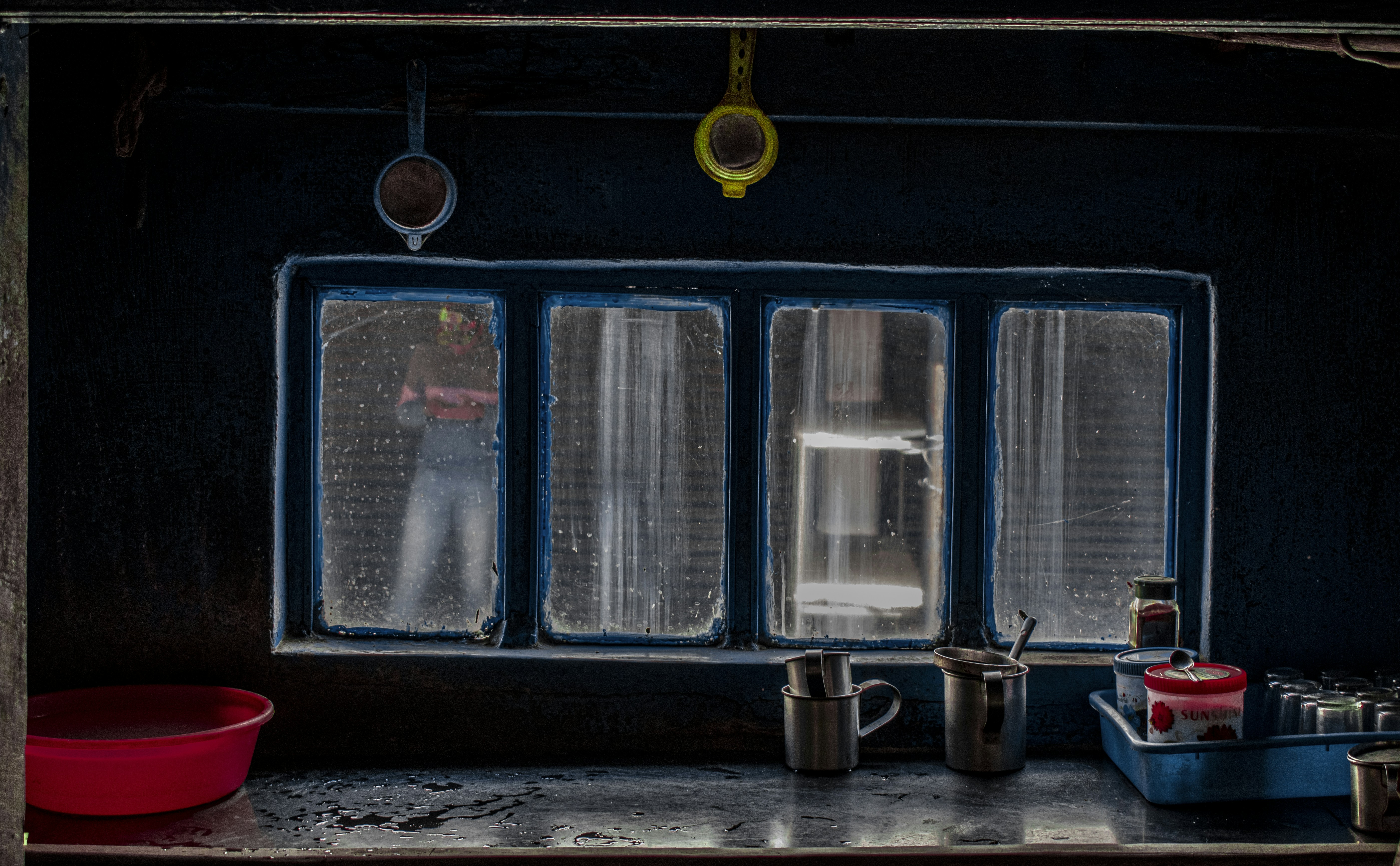 Blue-Framed Four-Pane Window Casts Quiet Light on a Weathered Kitchen