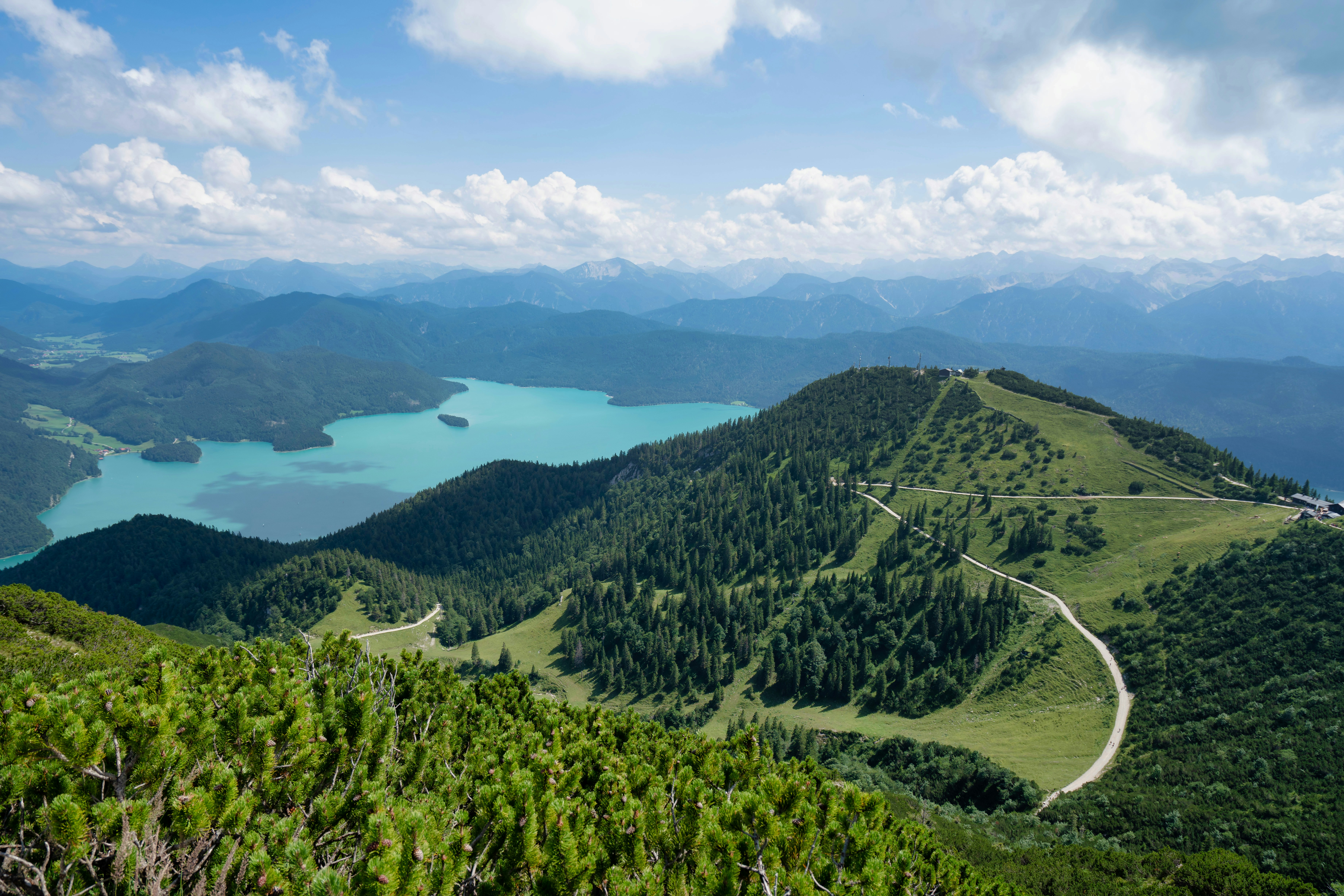 Vibrant lake surrounded by lush green hills under a partly cloudy sky.
