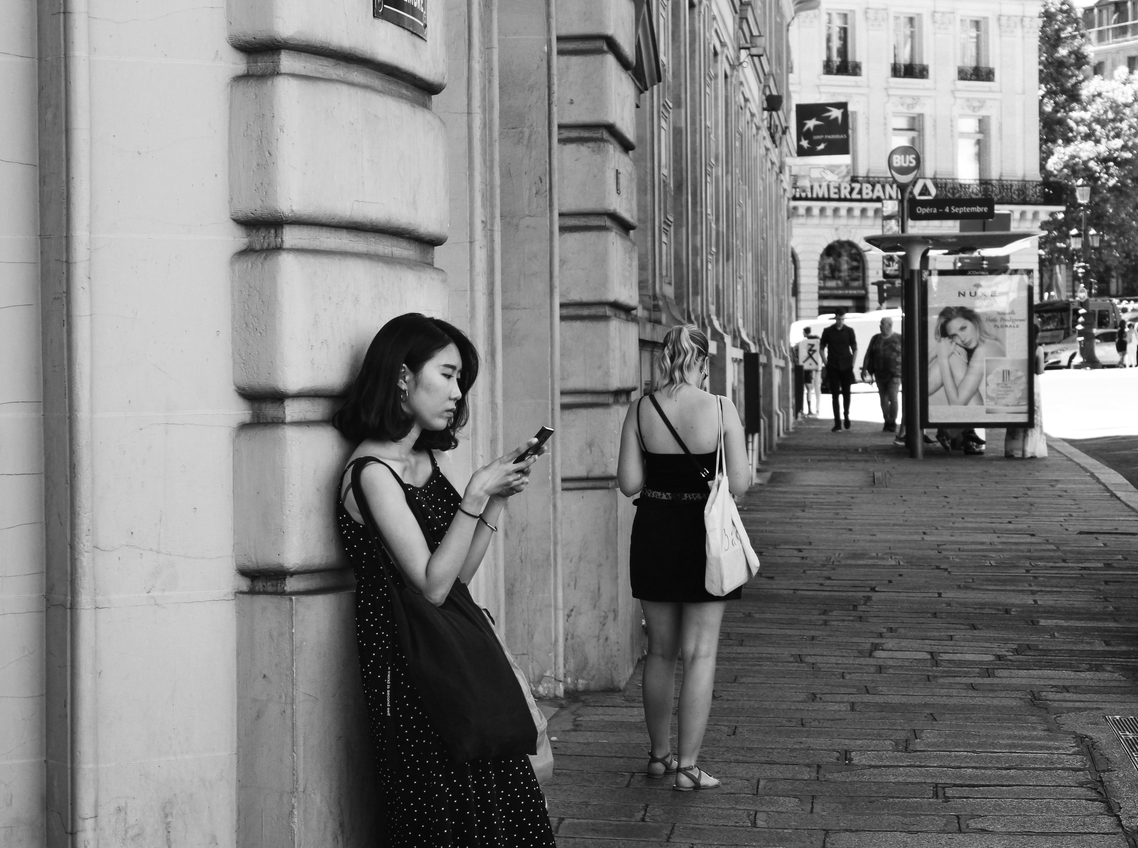 A graceful woman leaning on the wall in the street in Paris 🇫🇷 | woman in black tank top and skirt standing beside concrete building during daytime
