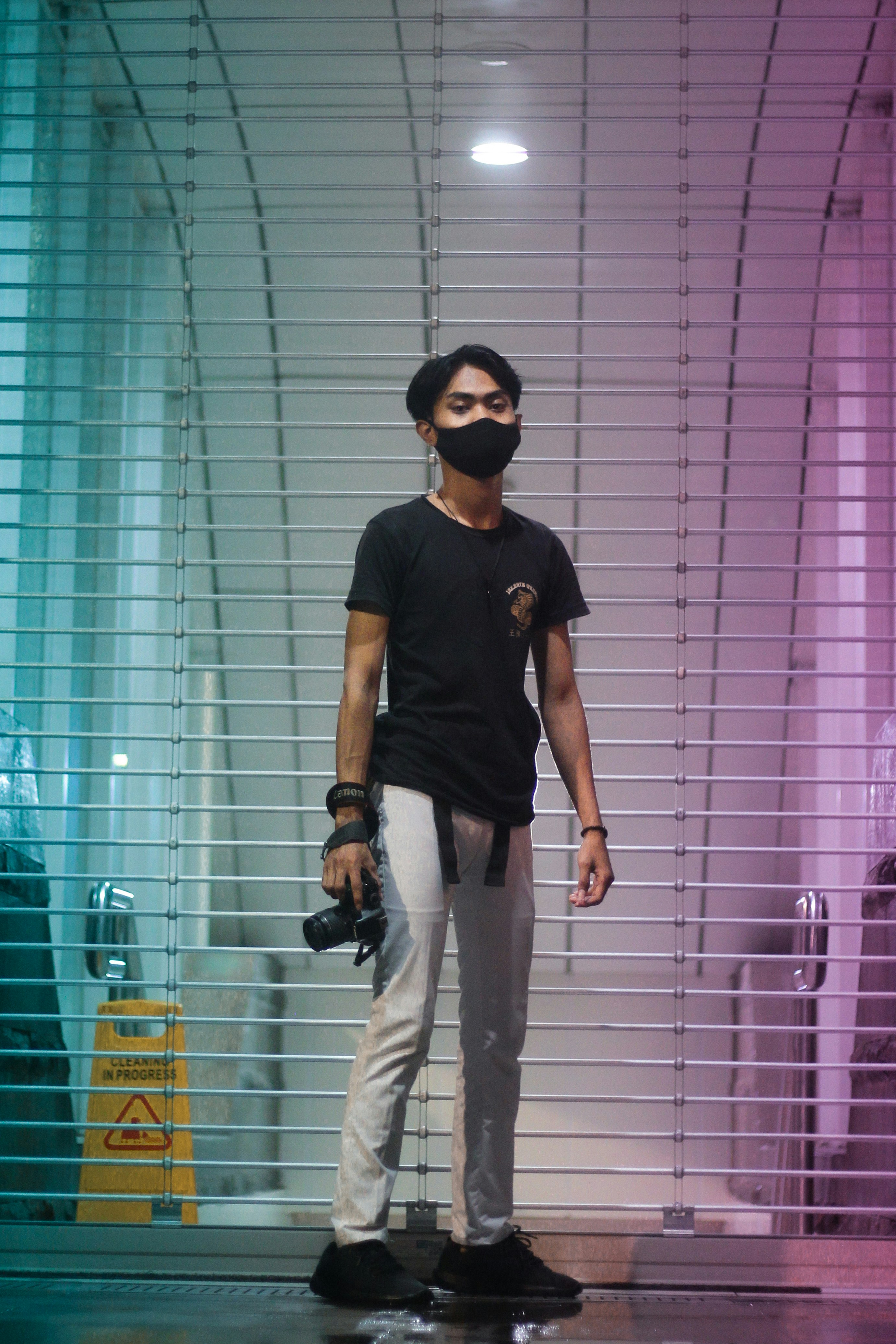 Masked Photographer Before a Color-Tinted Metal Shutter