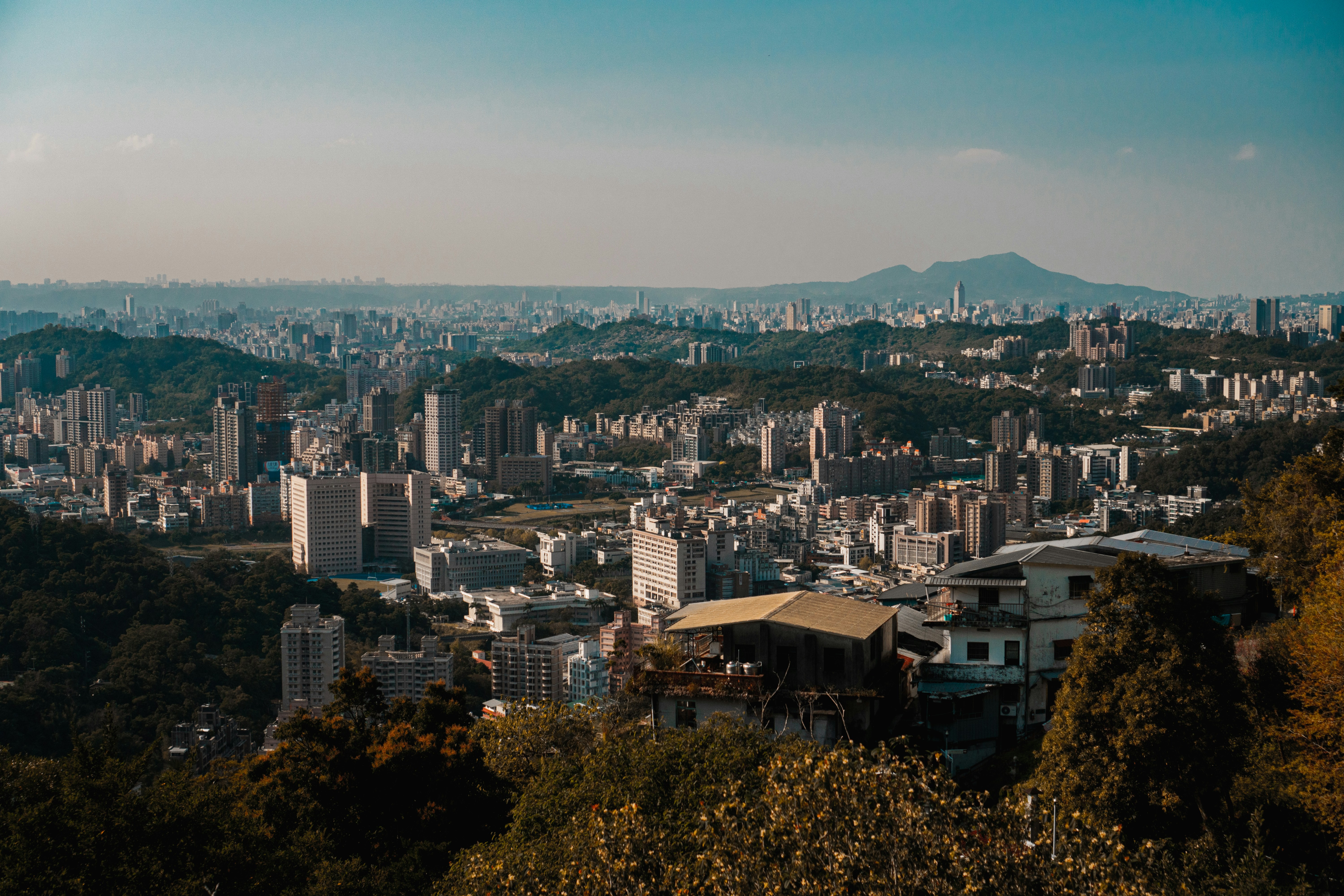 Cityscape with sprawling buildings set against distant mountains under a clear sky.