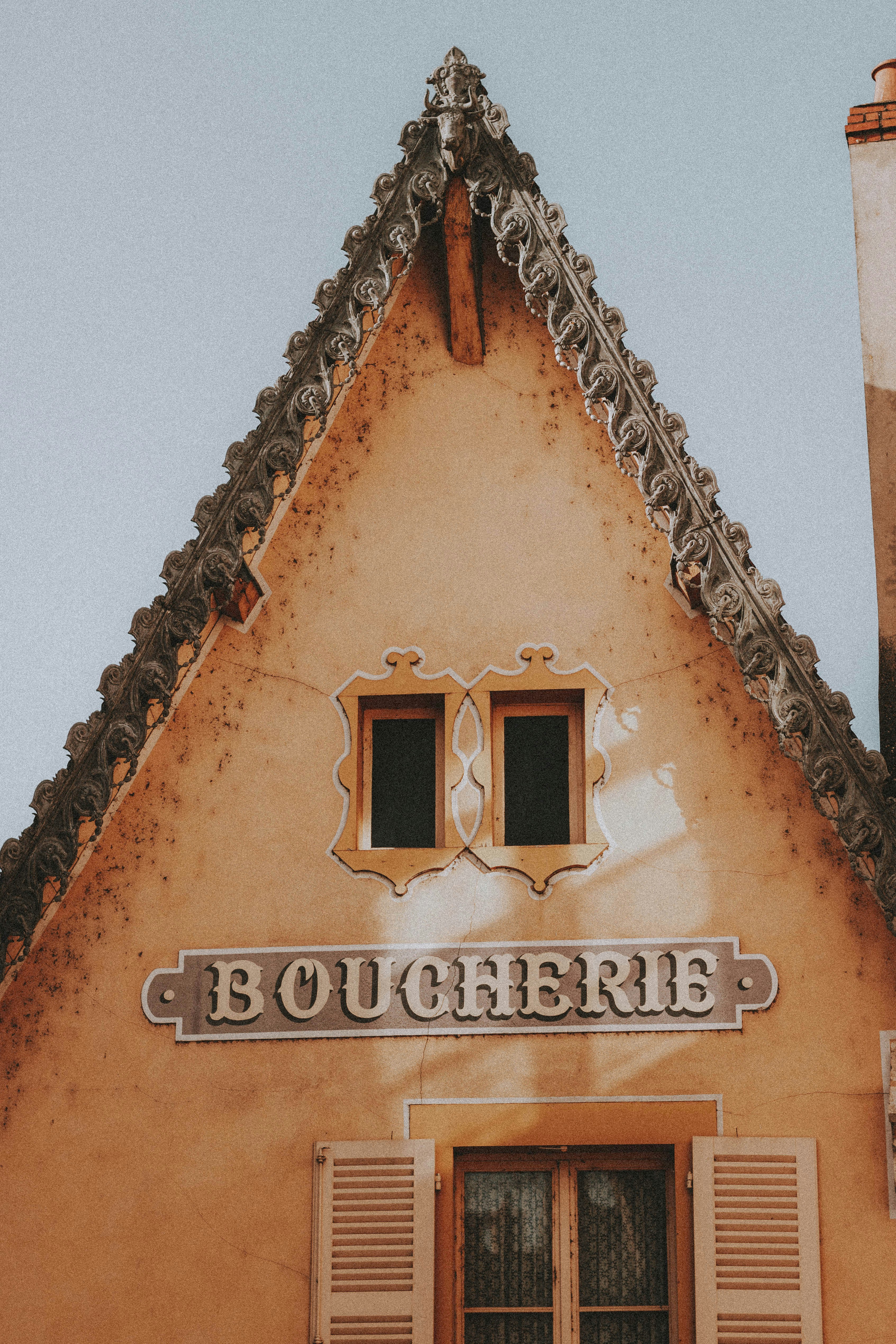 Historic building featuring intricate eaves and a prominent 'Boucherie' sign, showcasing classic architectural details.