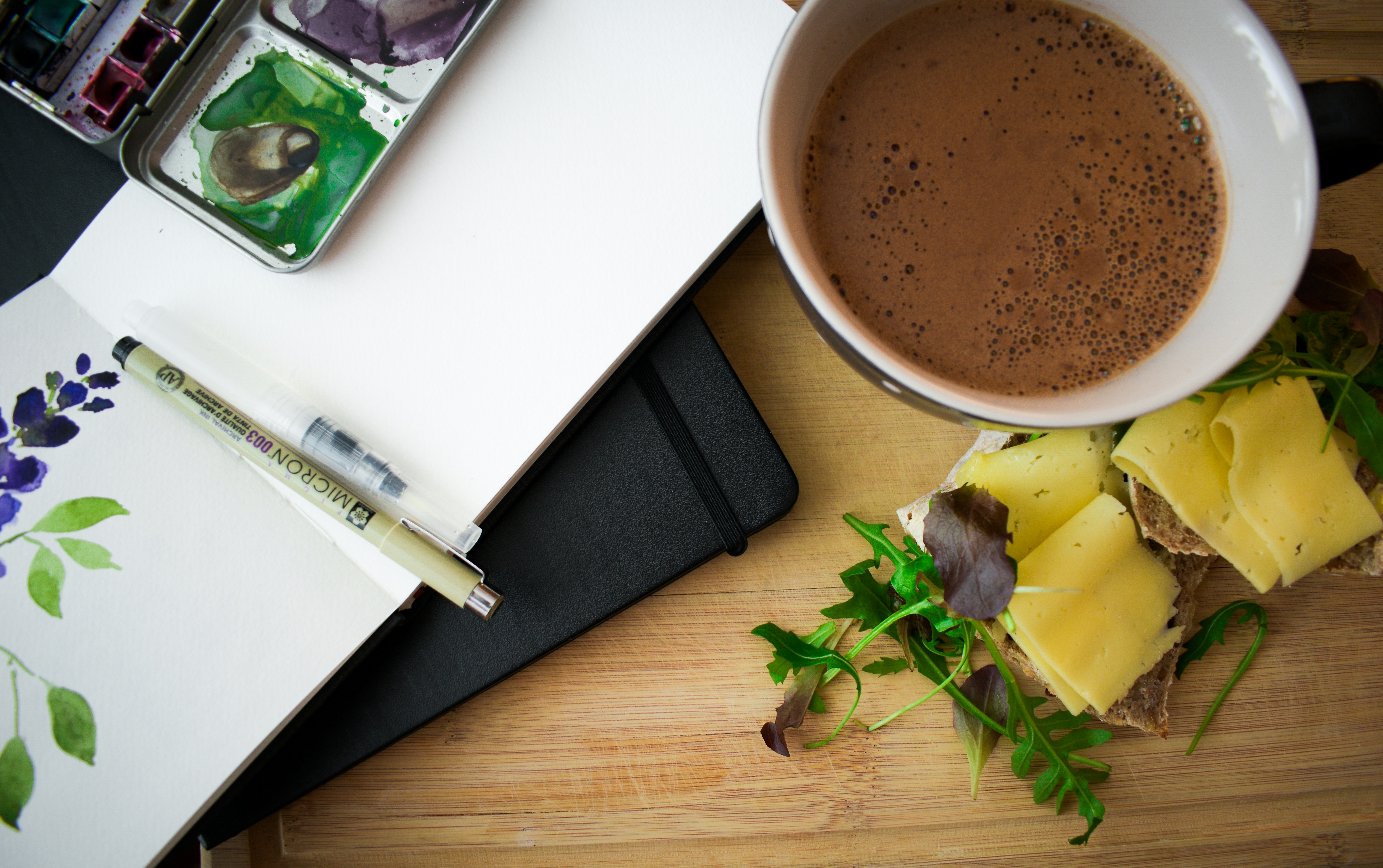 Melting Moments: Coffee, Cheese, and Sketches on a Wooden Desk