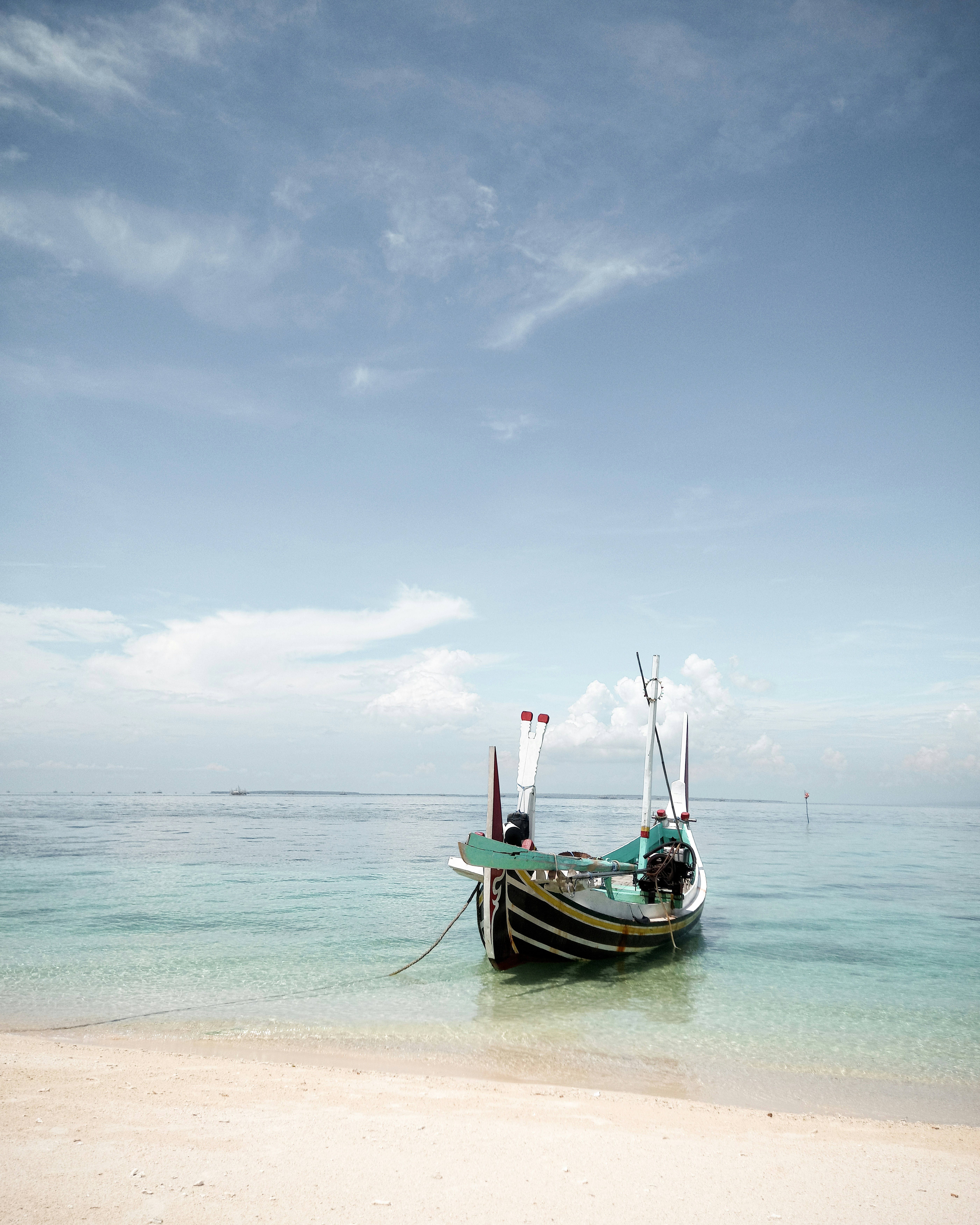 Traditional fishing boat anchored in calm turquoise waters under a clear sky.