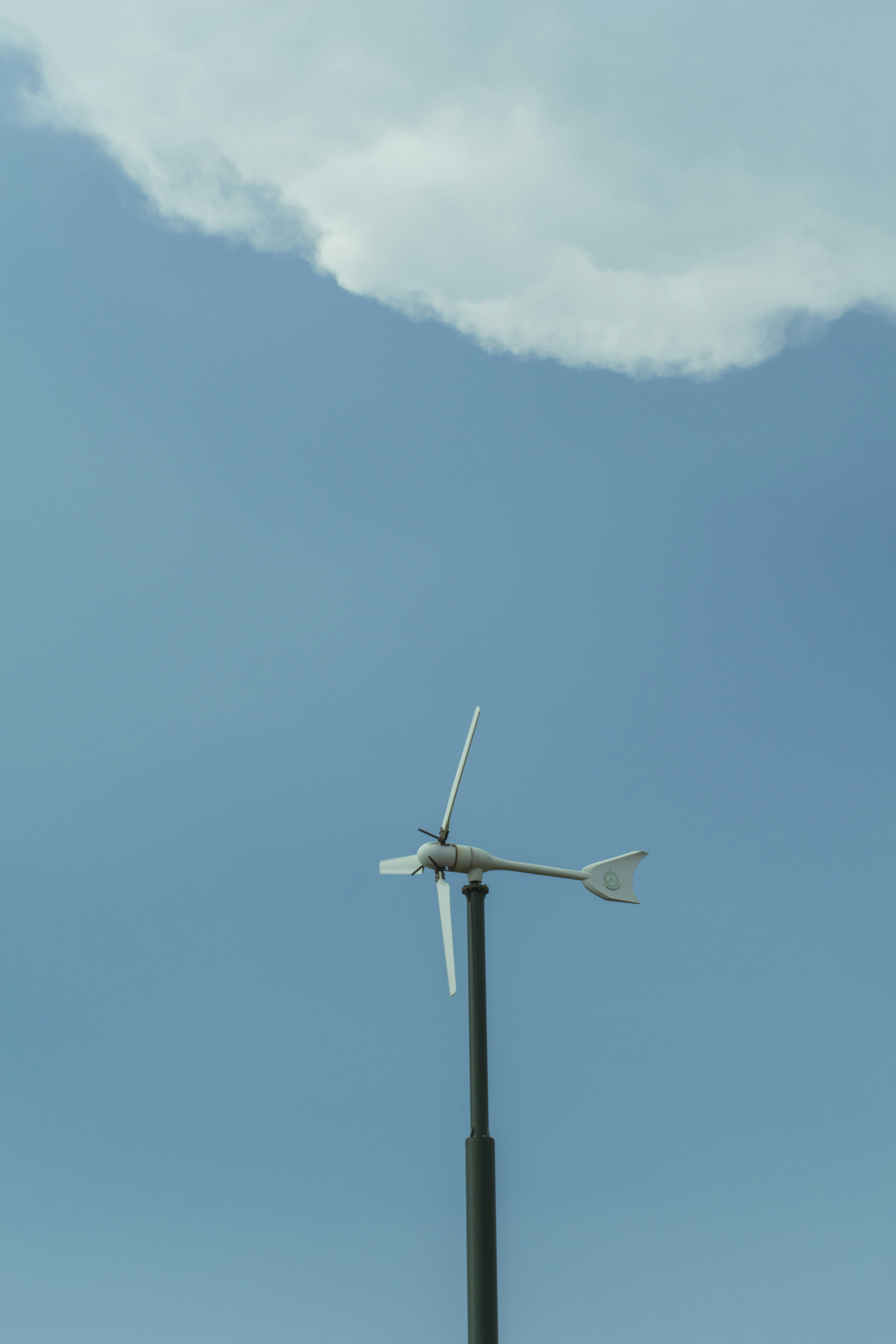 Minimalist Skyward Rod: A Wind Turbine Silhouette Against a Calm Blue