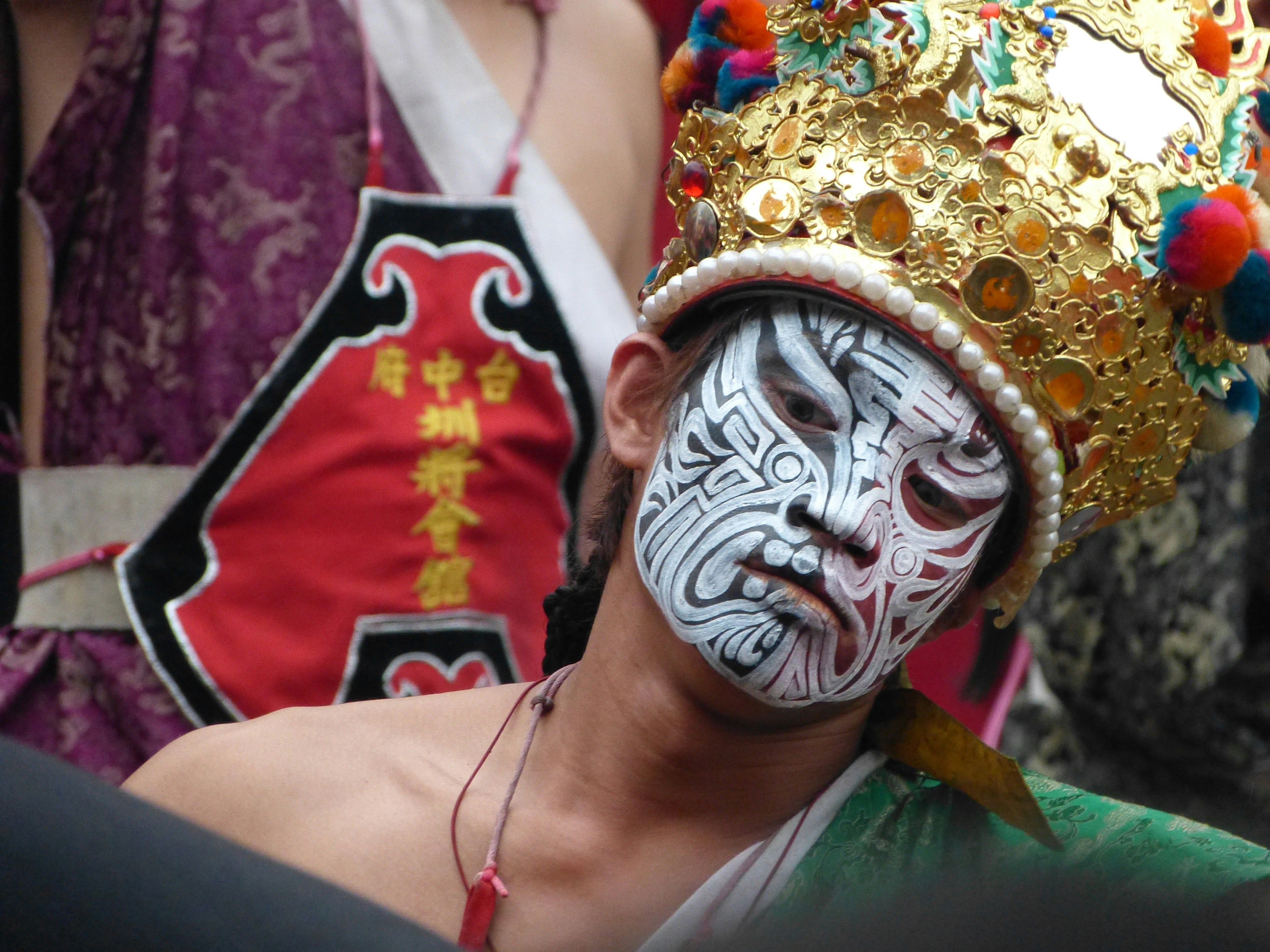 Person wearing intricate face paint and ornate headdress, participating in a cultural ceremony.