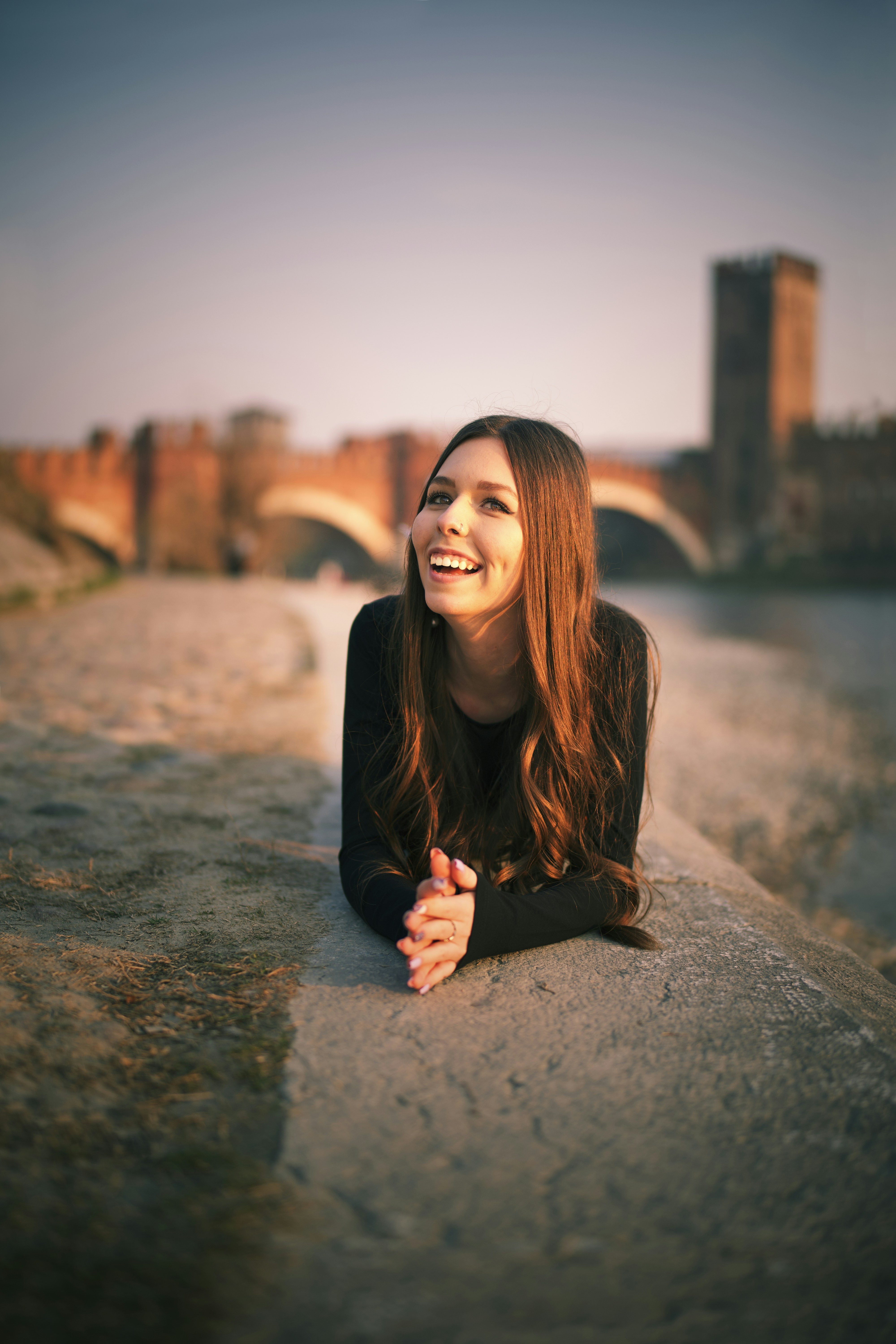 Laughing Portrait by the River: Warm Sunset on an Ancient Bridge