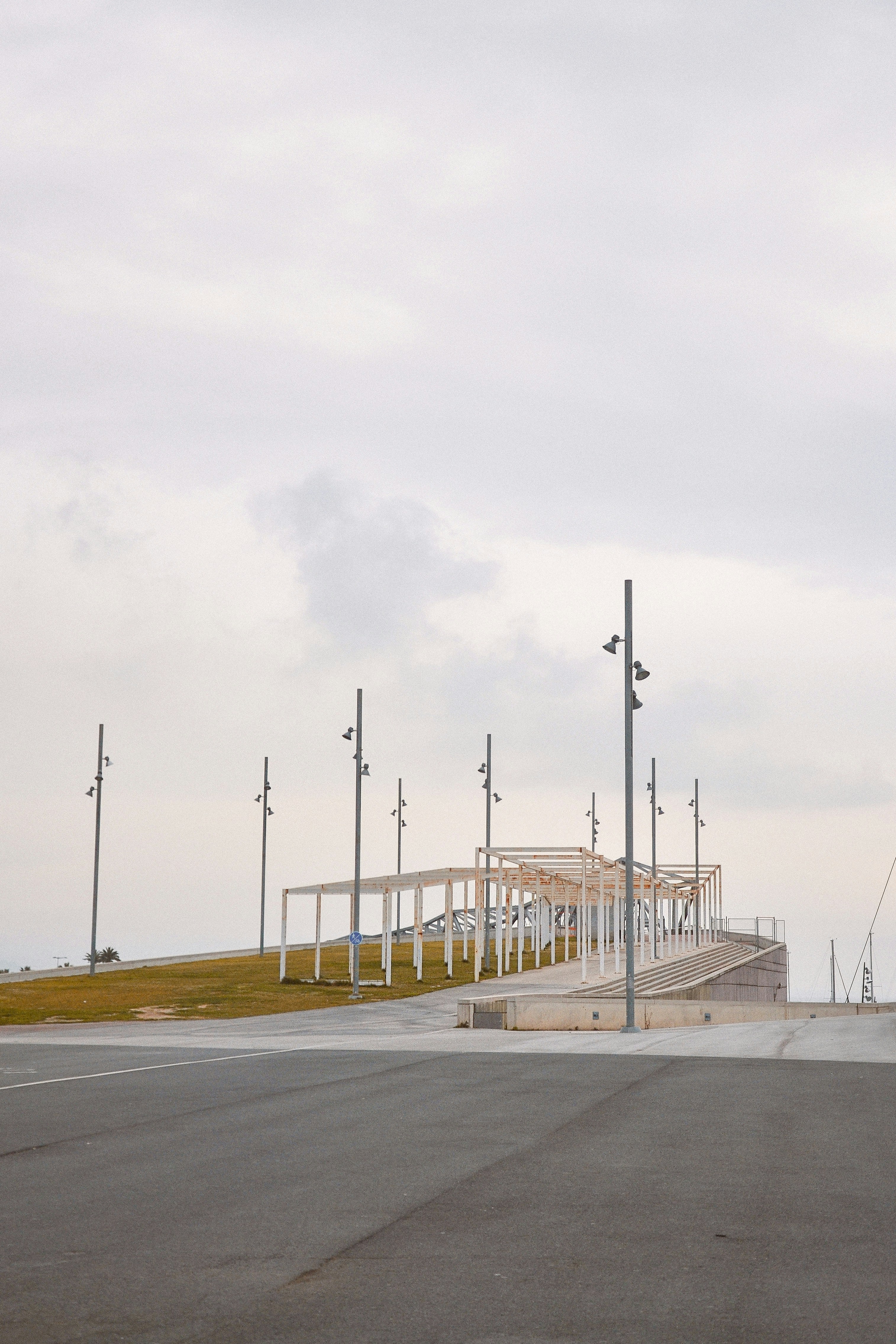 Muted Promenade: White Framework and Lamp Posts along a Sea-Edge Walkway