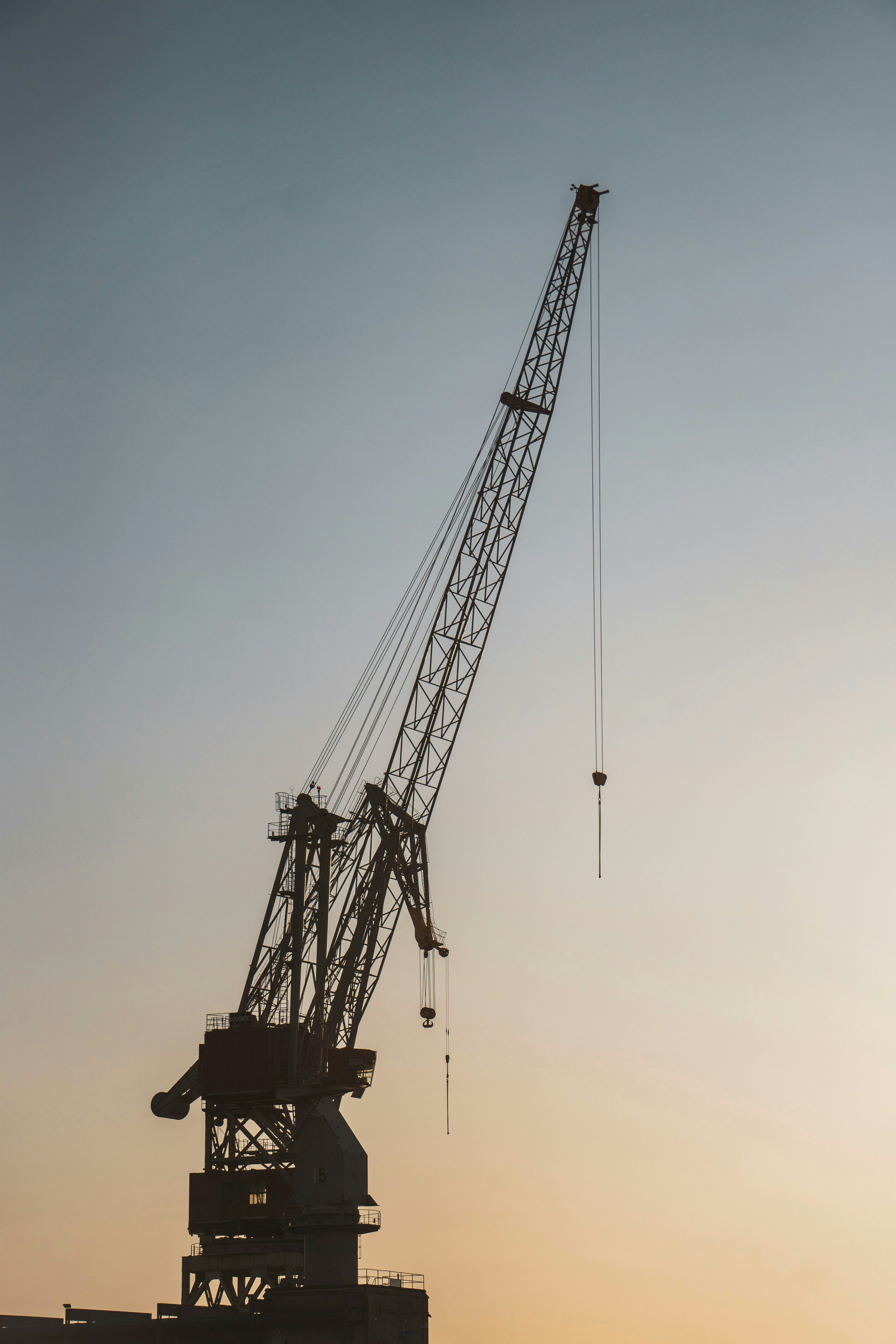 Silhouette of a towering crane against a pastel sunset, emphasizing the intersection of industry and nature.