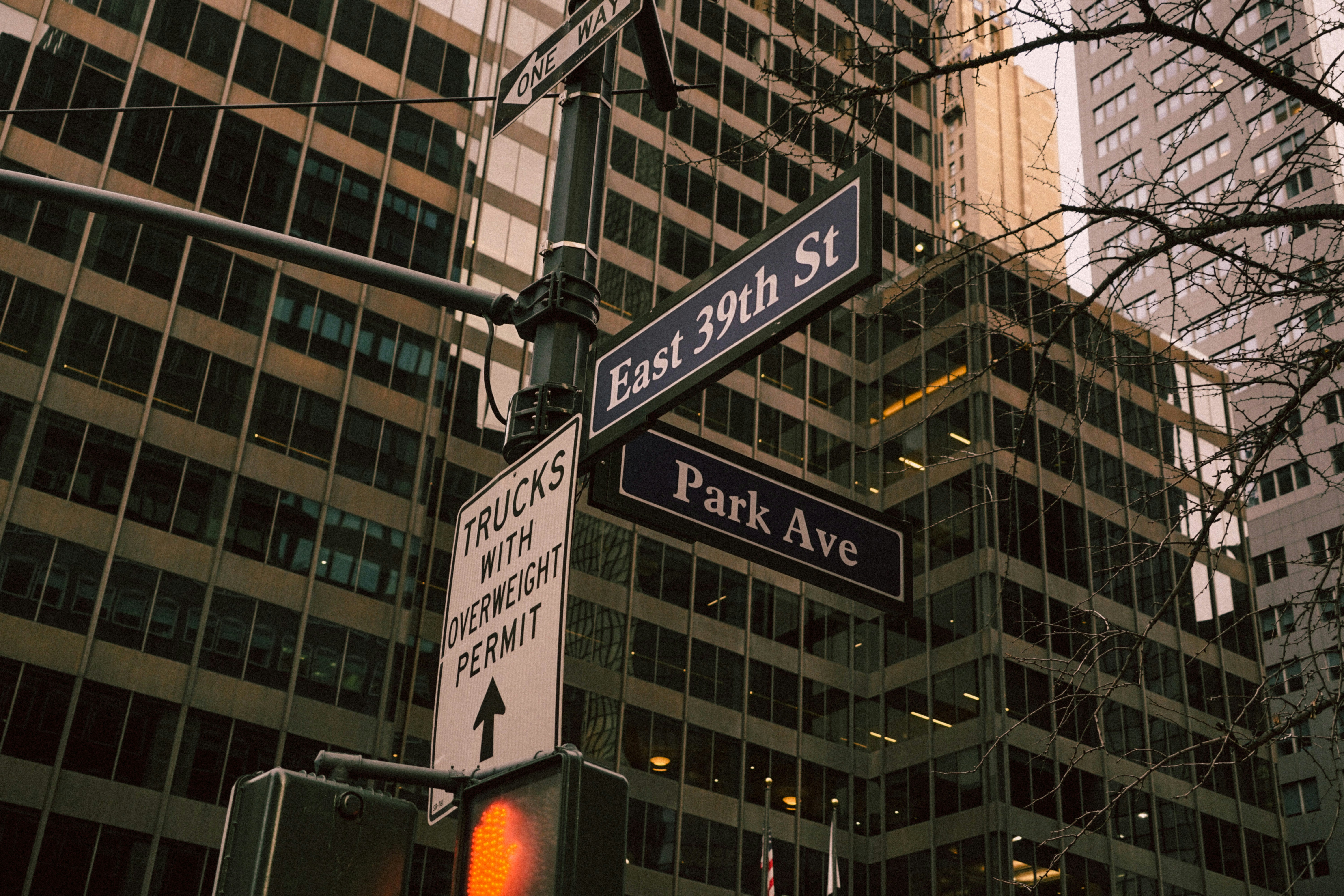 Street signs indicating East 39th Street and Park Avenue amidst towering skyscrapers. A traffic sign for overweight trucks is also visible.