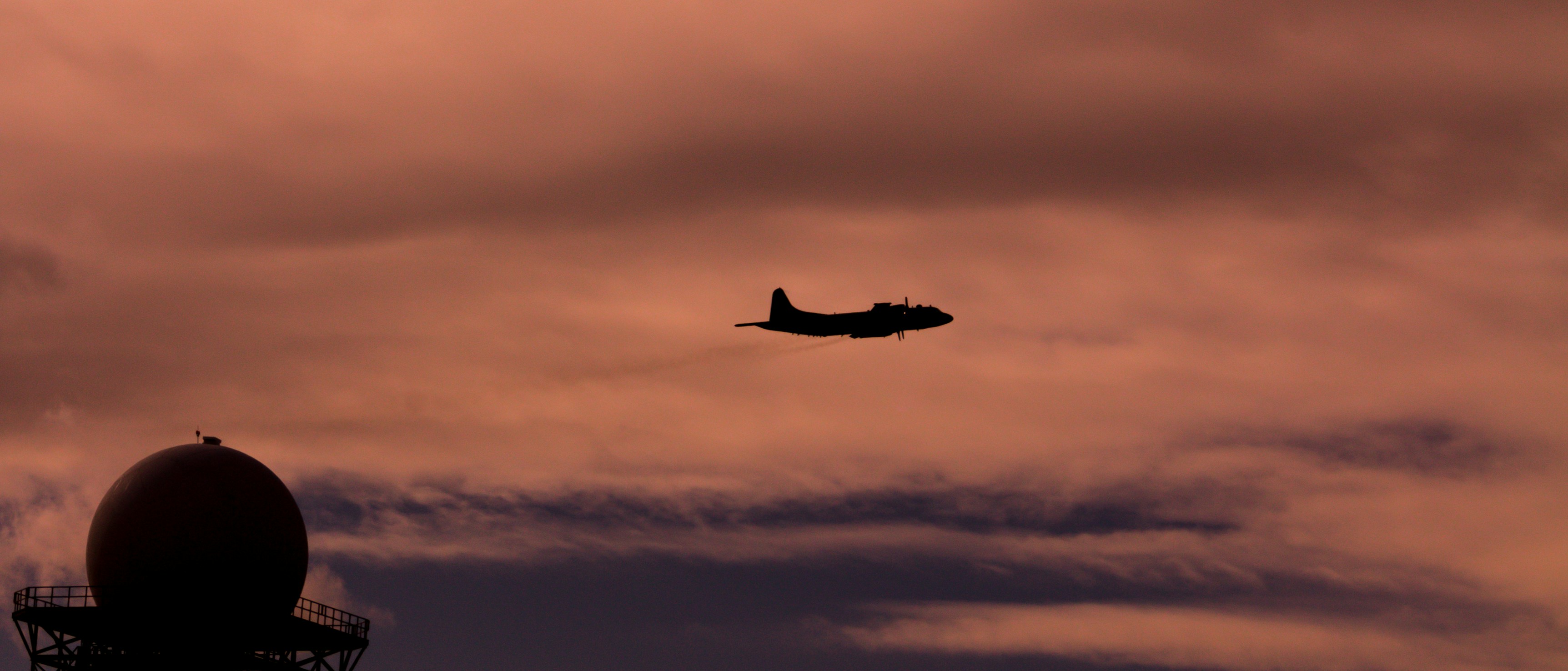 Ember Horizon: Jet Silhouette Skims Past a Weather Radar Dome at Dusk