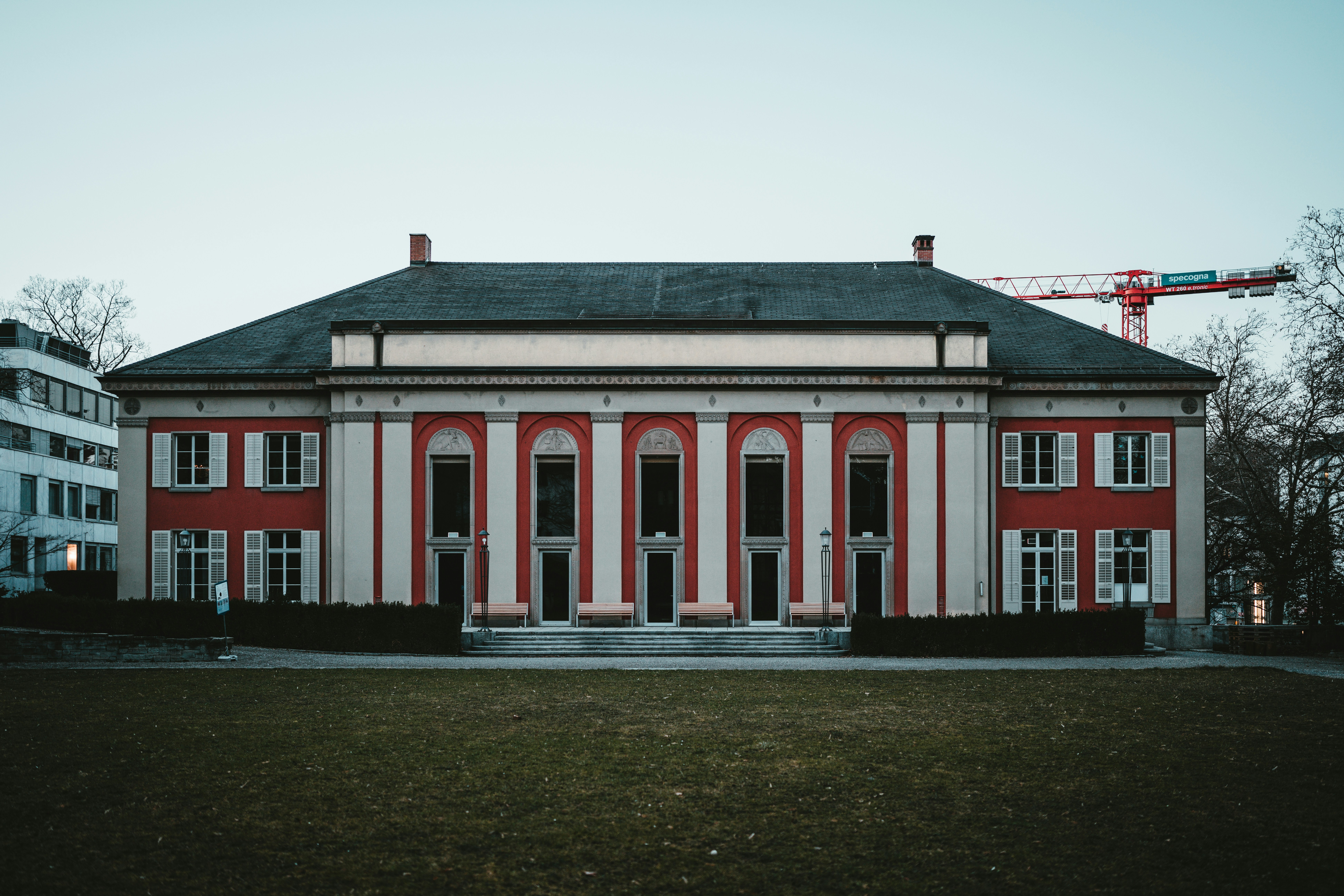 Historic building with striking red and white columns, set against a clear sky, showcasing a blend of classic and contemporary architecture.