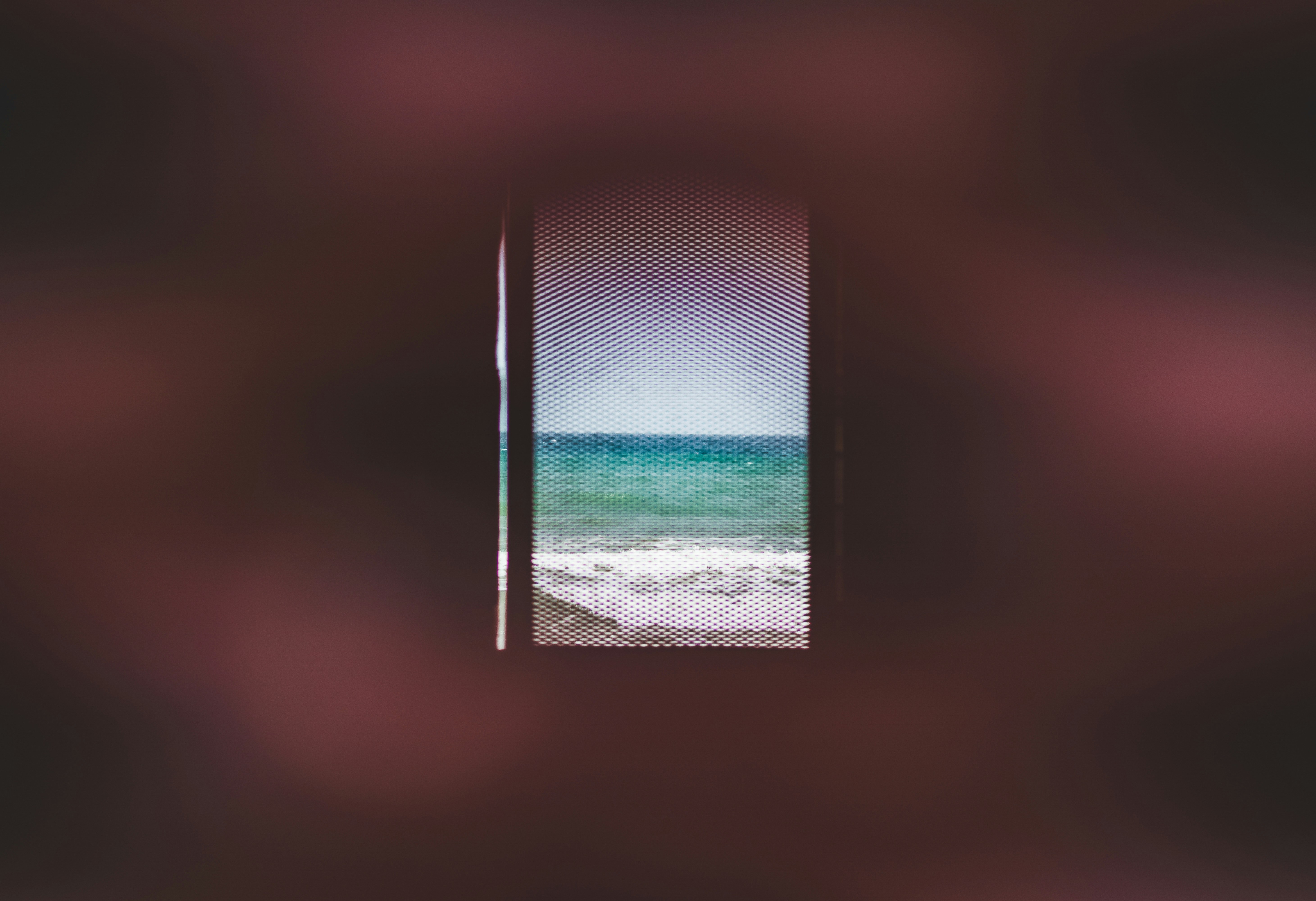 Window to the Quiet Coast: Beach Framed by a Narrow Mesh