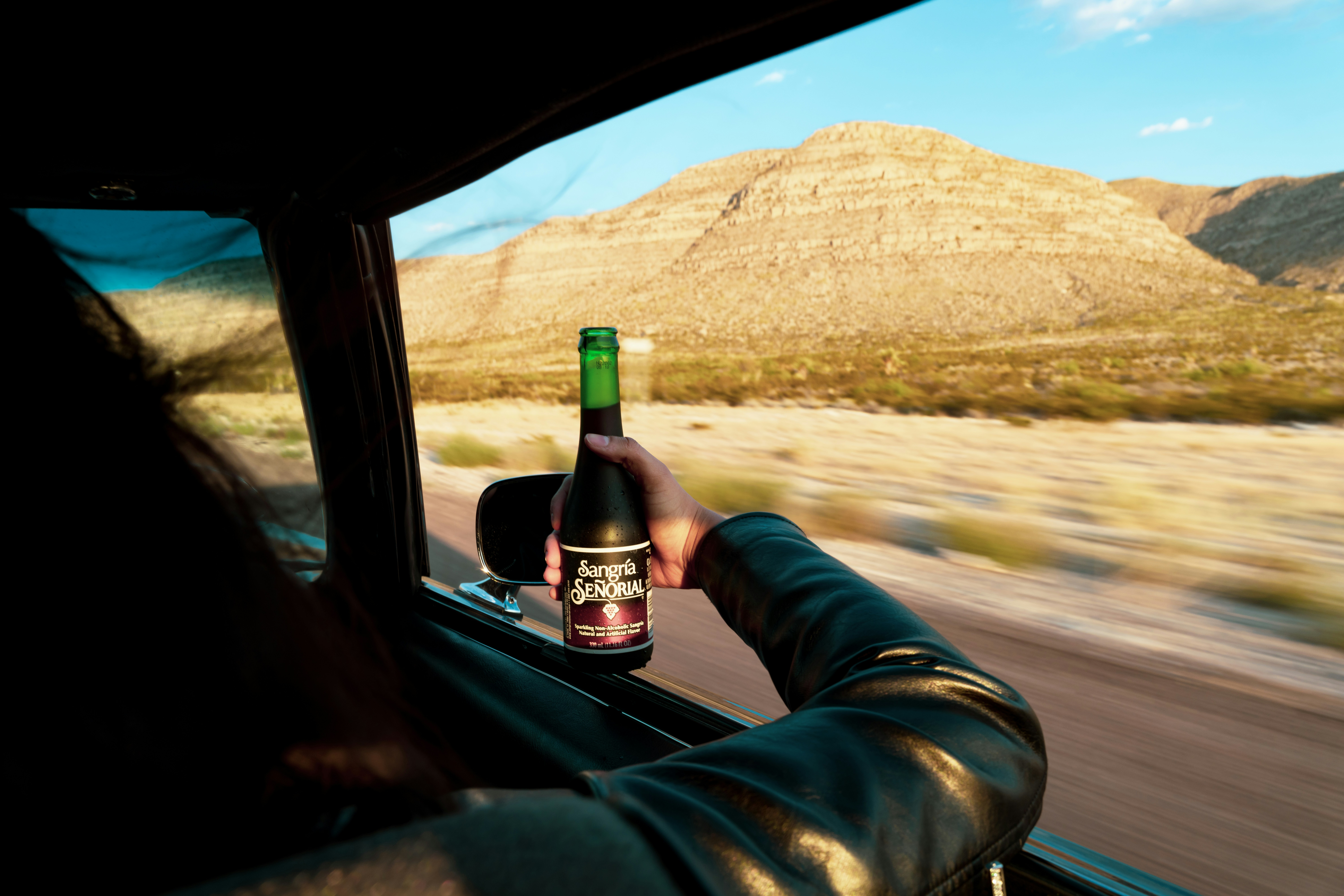Desert Window Drive: a Bottle Framed by Golden Hills in Motion