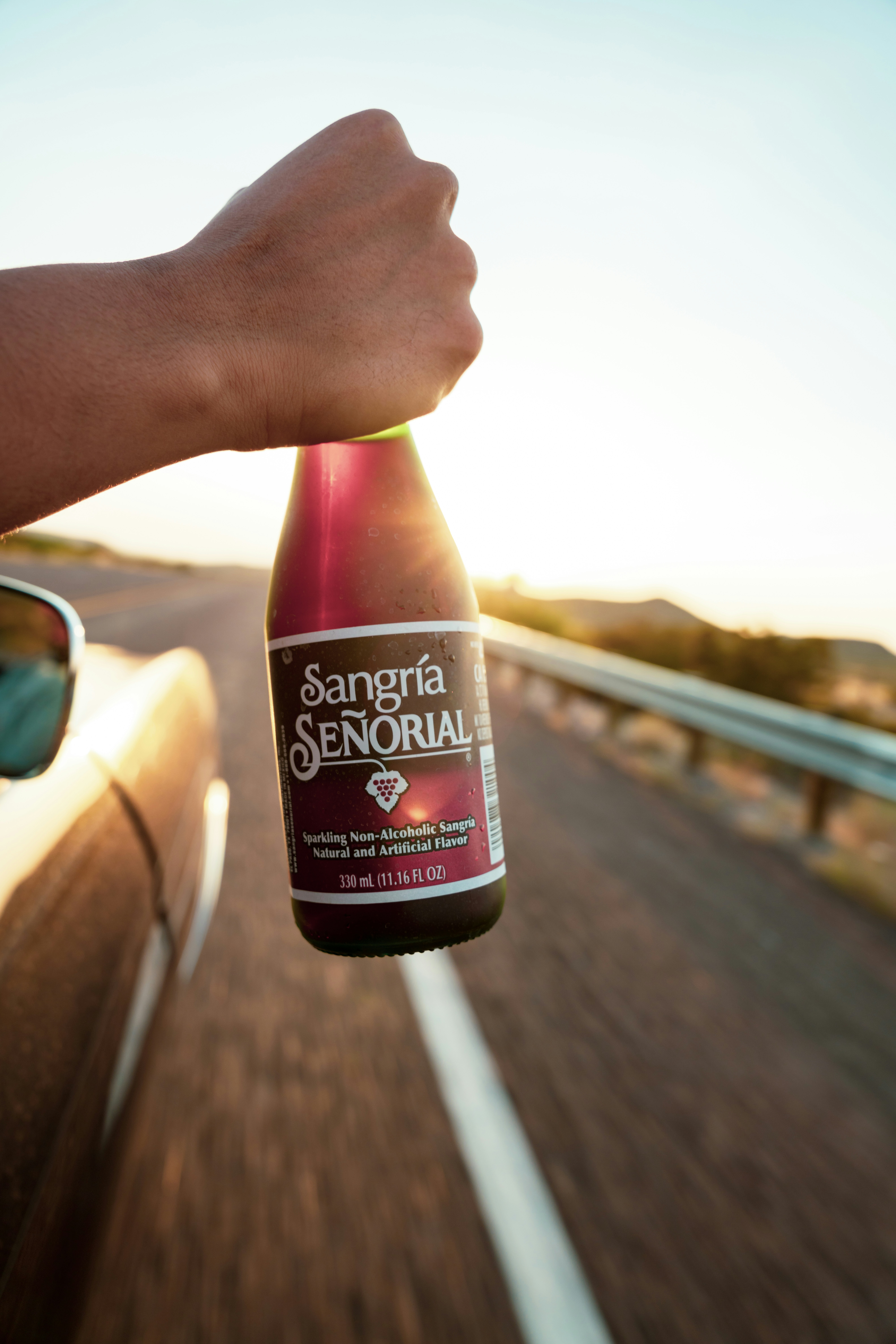 Golden Hour Grip: Sangría Senorial Clutched on a Sunlit Highway