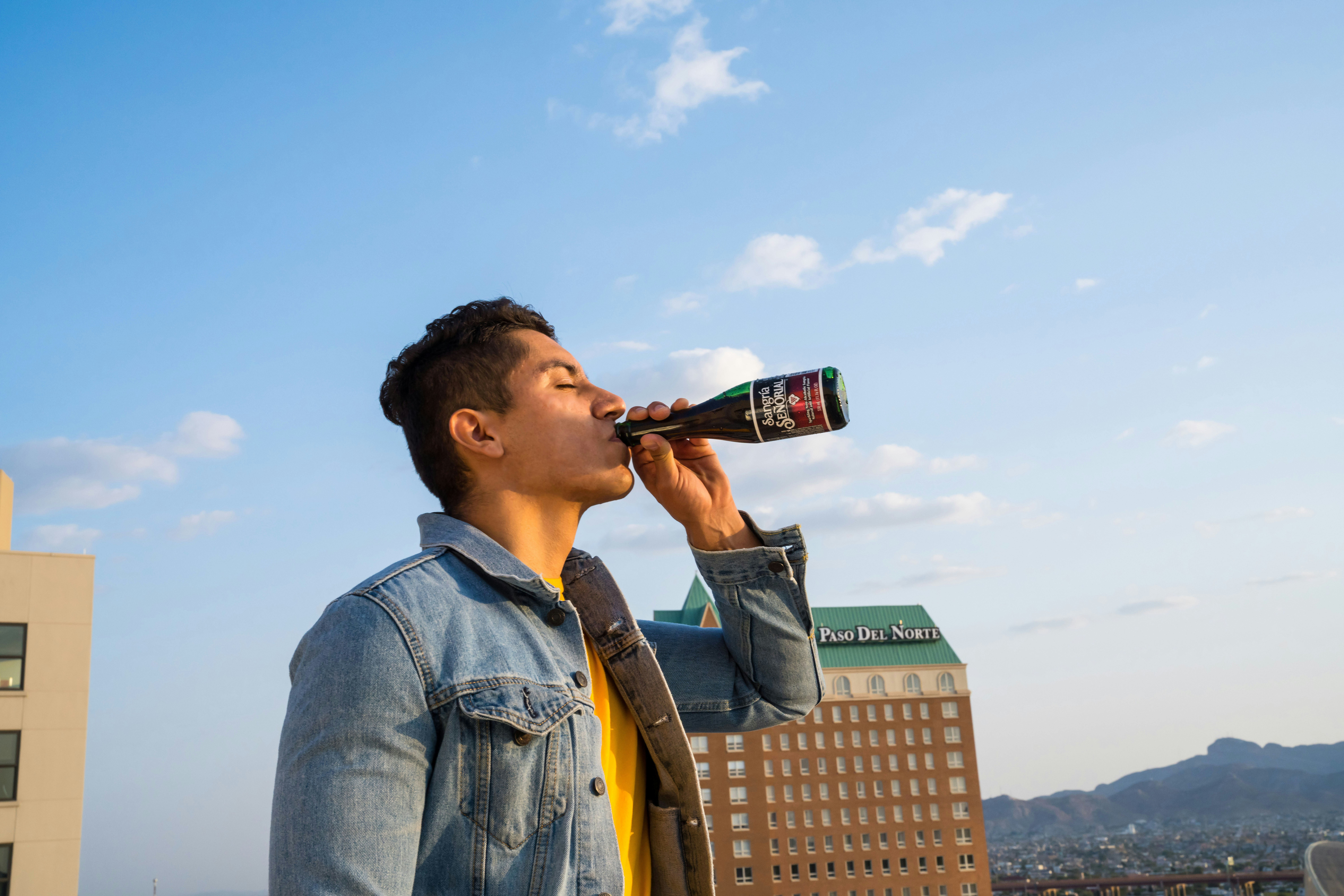 Rooftop Toast: Denim-Clad Figure Embraces the Cityscape