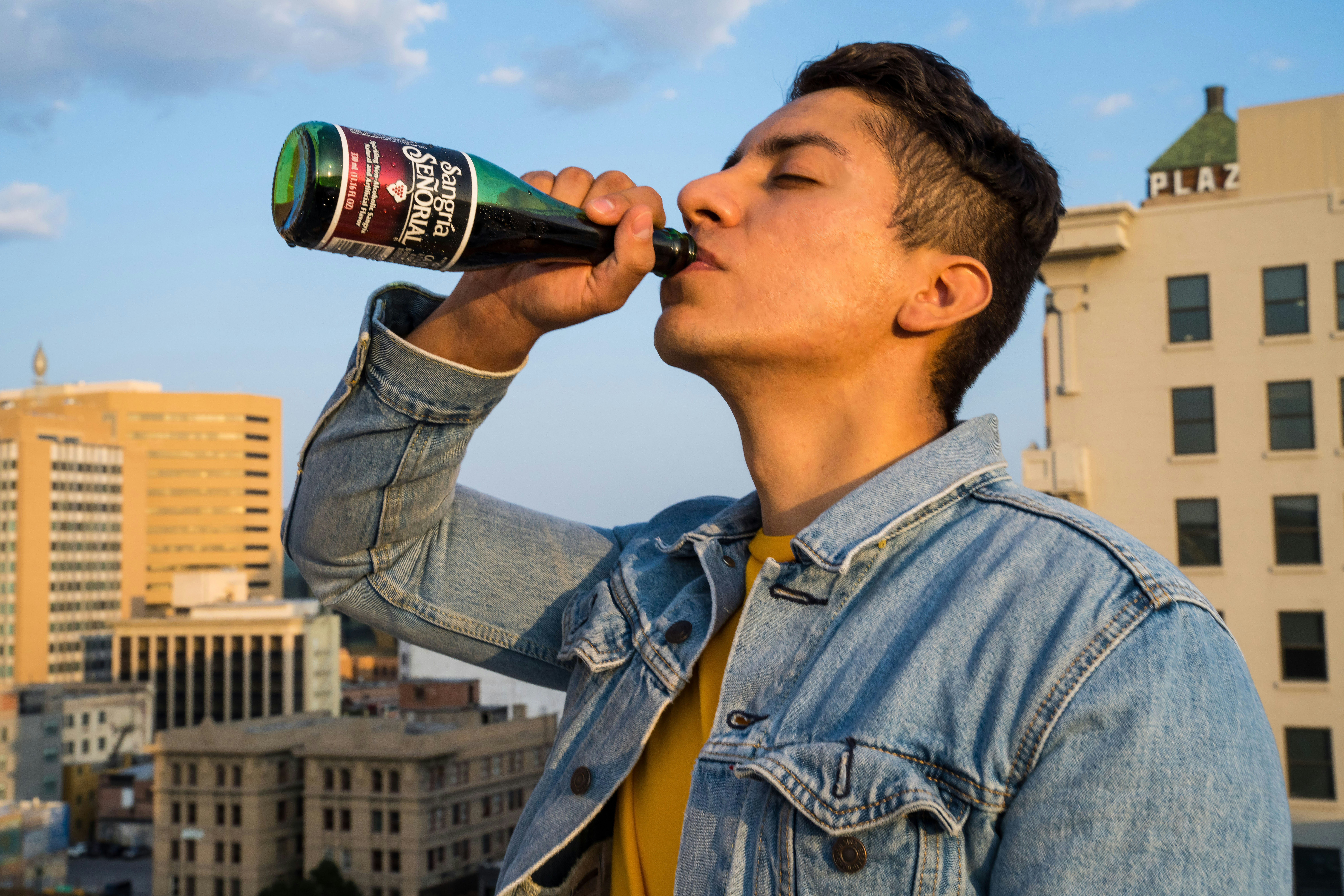 Golden Hour Rooftop Toast: Denim-Clad Figure Against a Cityscape