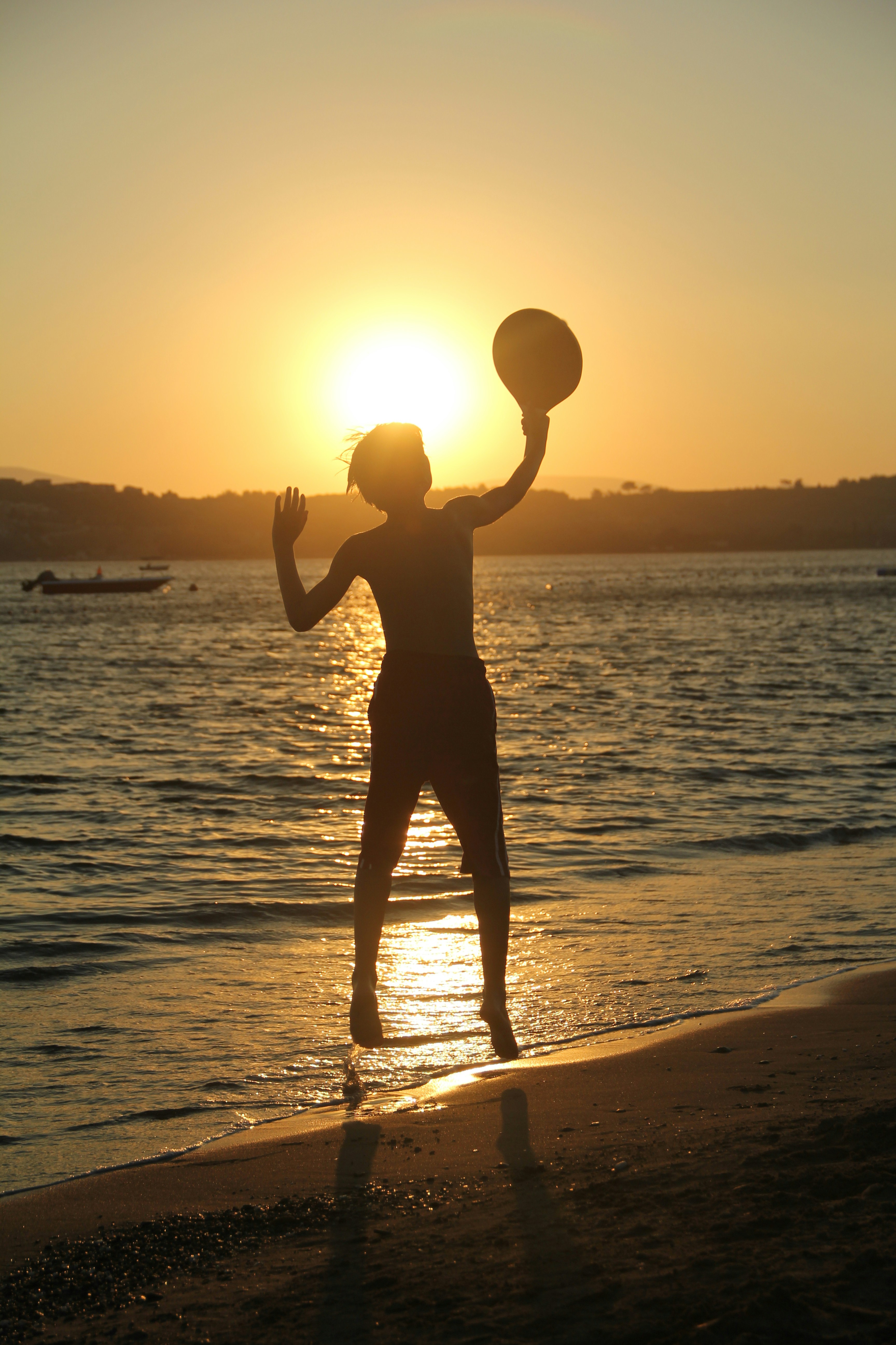 Silhouette Leap at Sunset: Hat Toss Over Quiet Waters