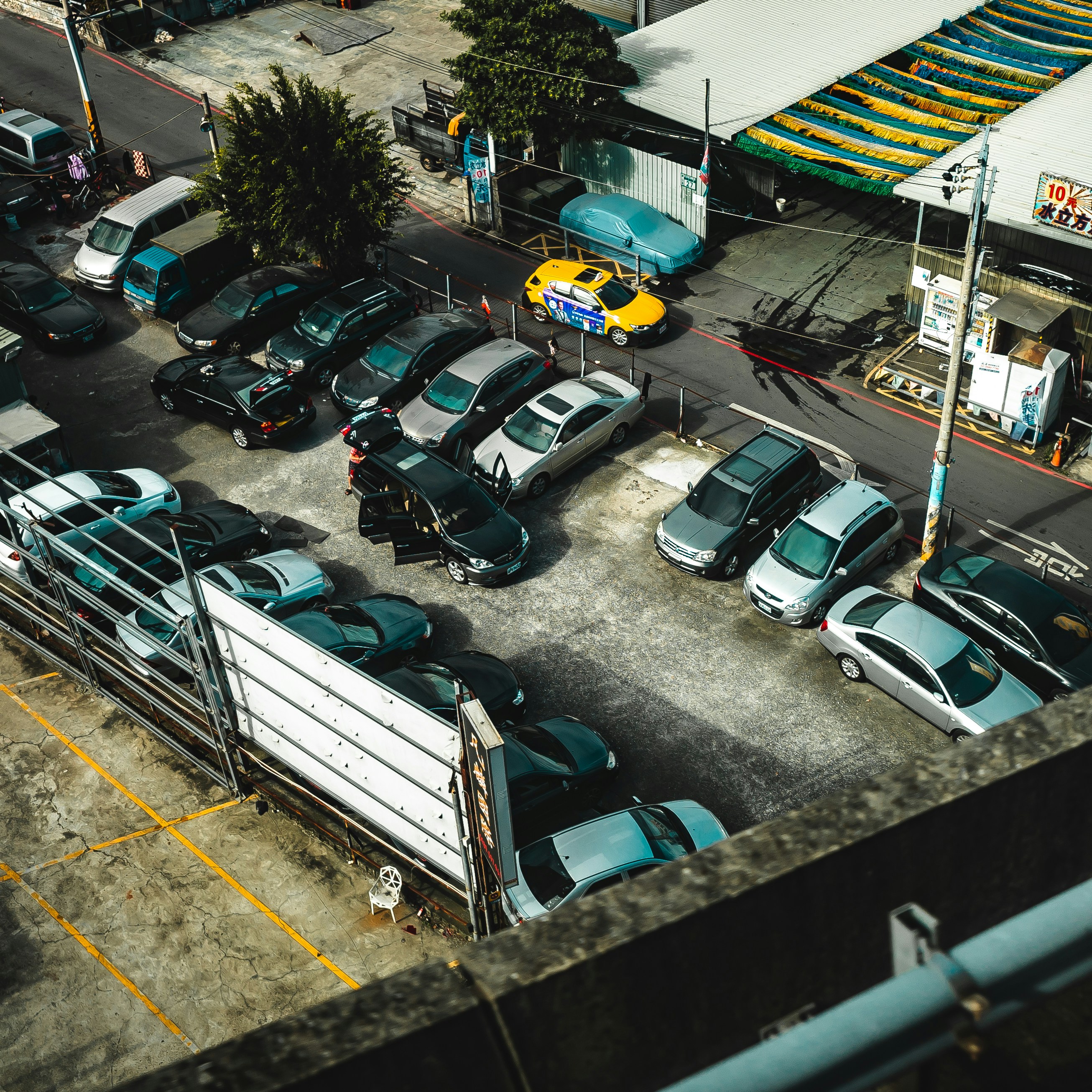 Yellow Taxi Amid Rows of Steel: An Aerial Look at a Busy Parking Lot