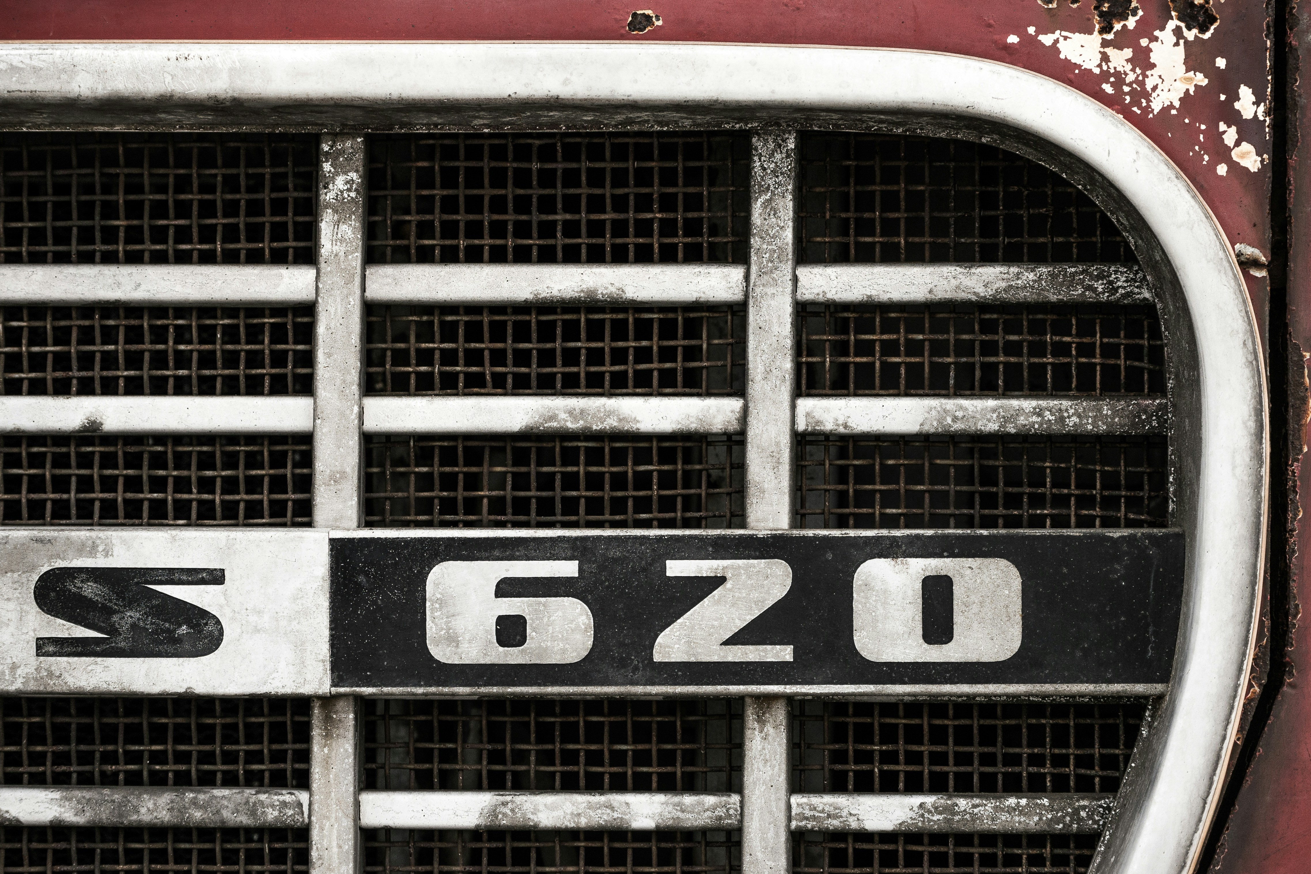 Close-up of a weathered S620 emblem on an antique vehicle, showcasing the intricate details and textures of aging metal and paint.