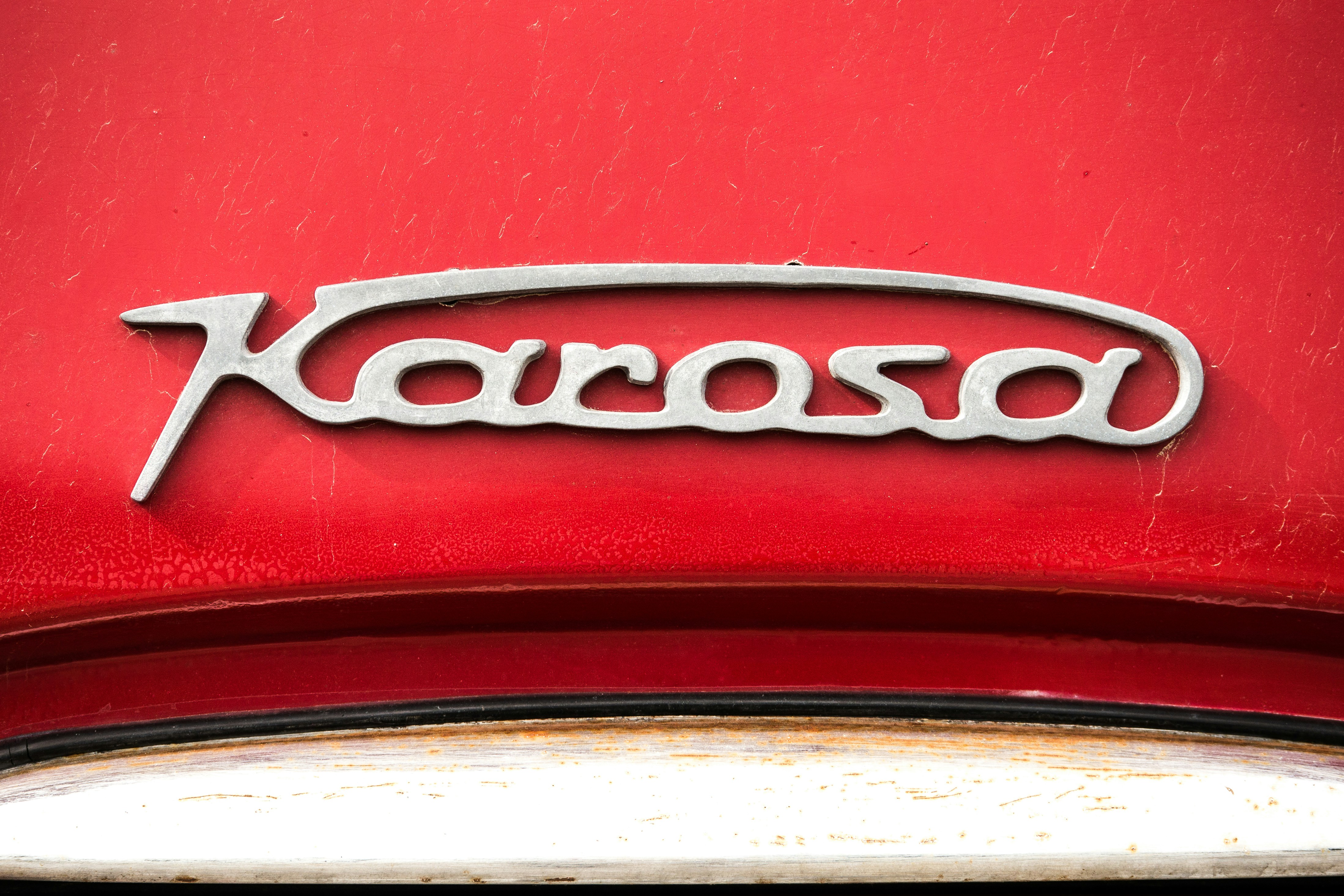 Karosa Emblem Gleams on Weathered Red Car Panel