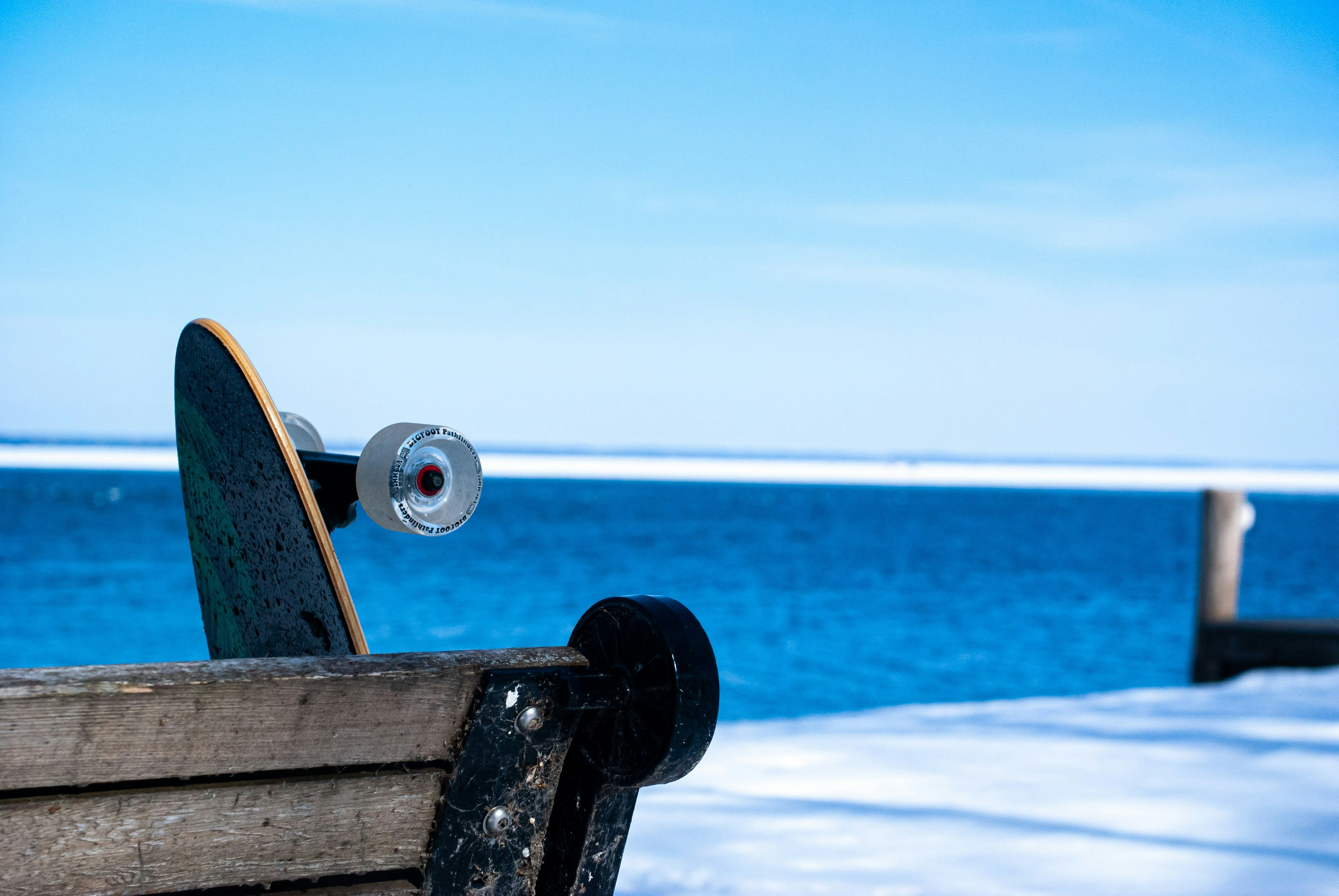 Blue Horizon, Snow-Dusted Deck: Skateboard Resting on a Weathered Pier Rail