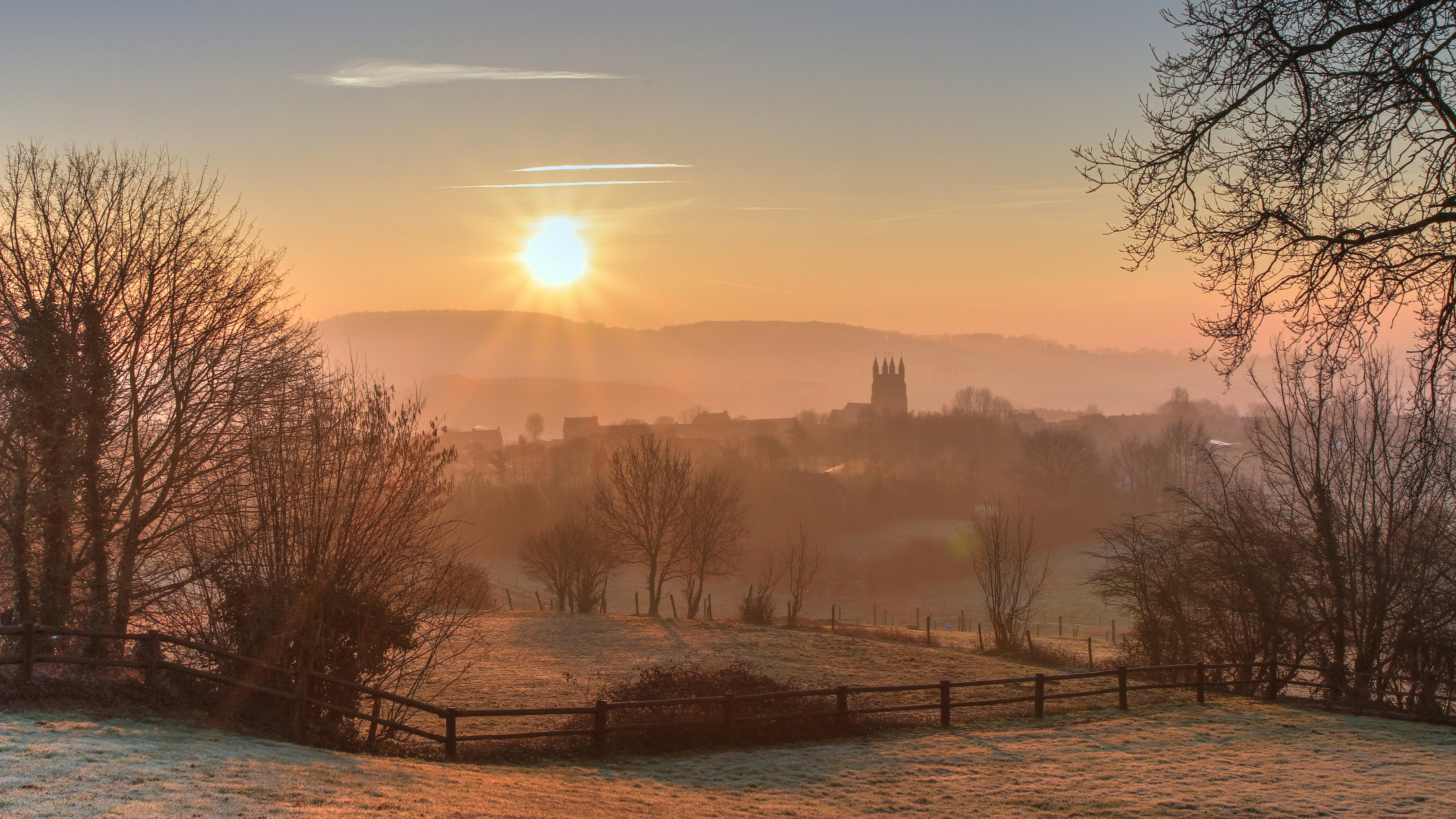 Dawn Over the Valley: Sunlit Fence and Silhouetted Village