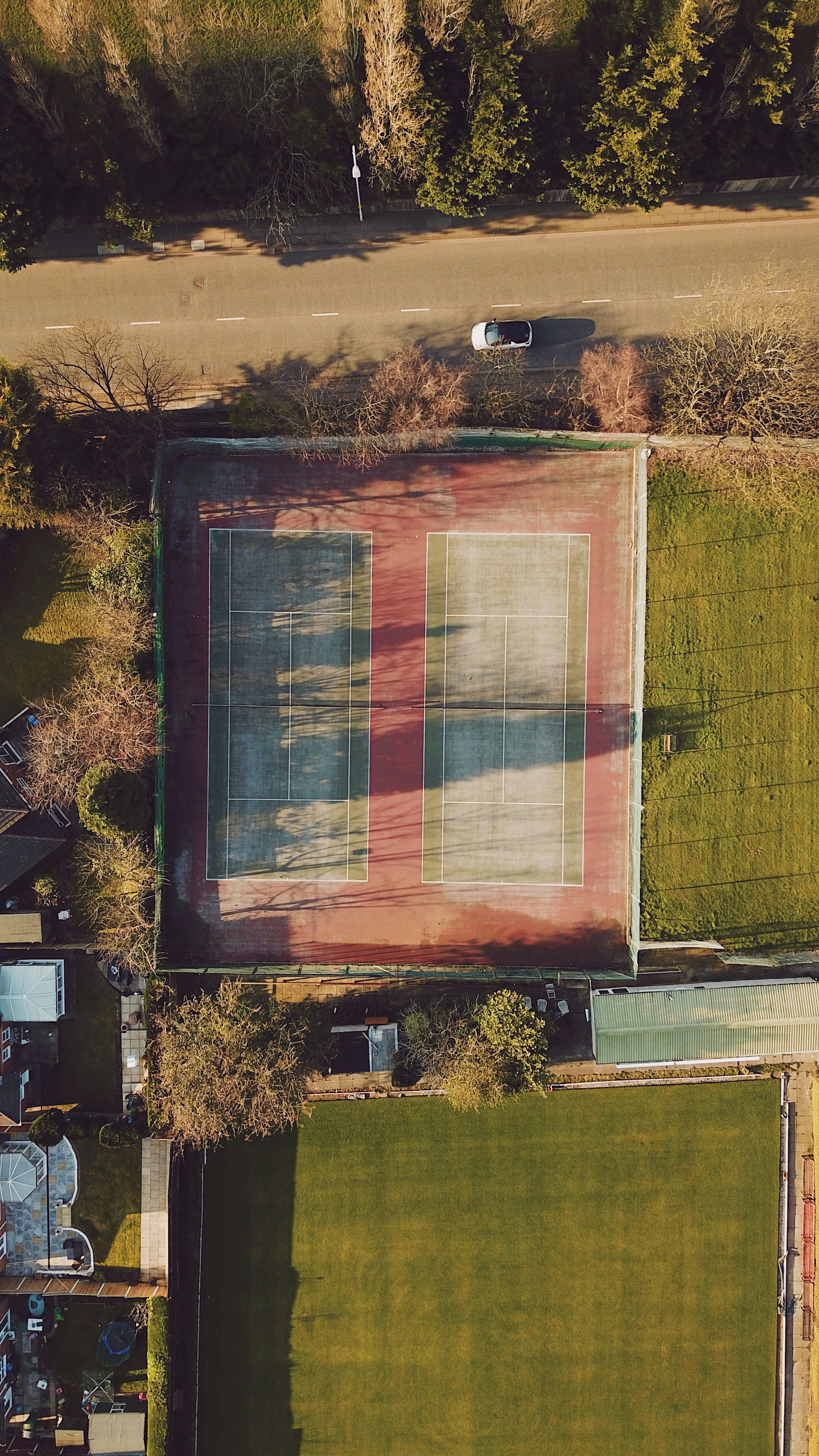 Aerial View: Dual Tennis Courts on a Red Rooftop Surrounded by Trees