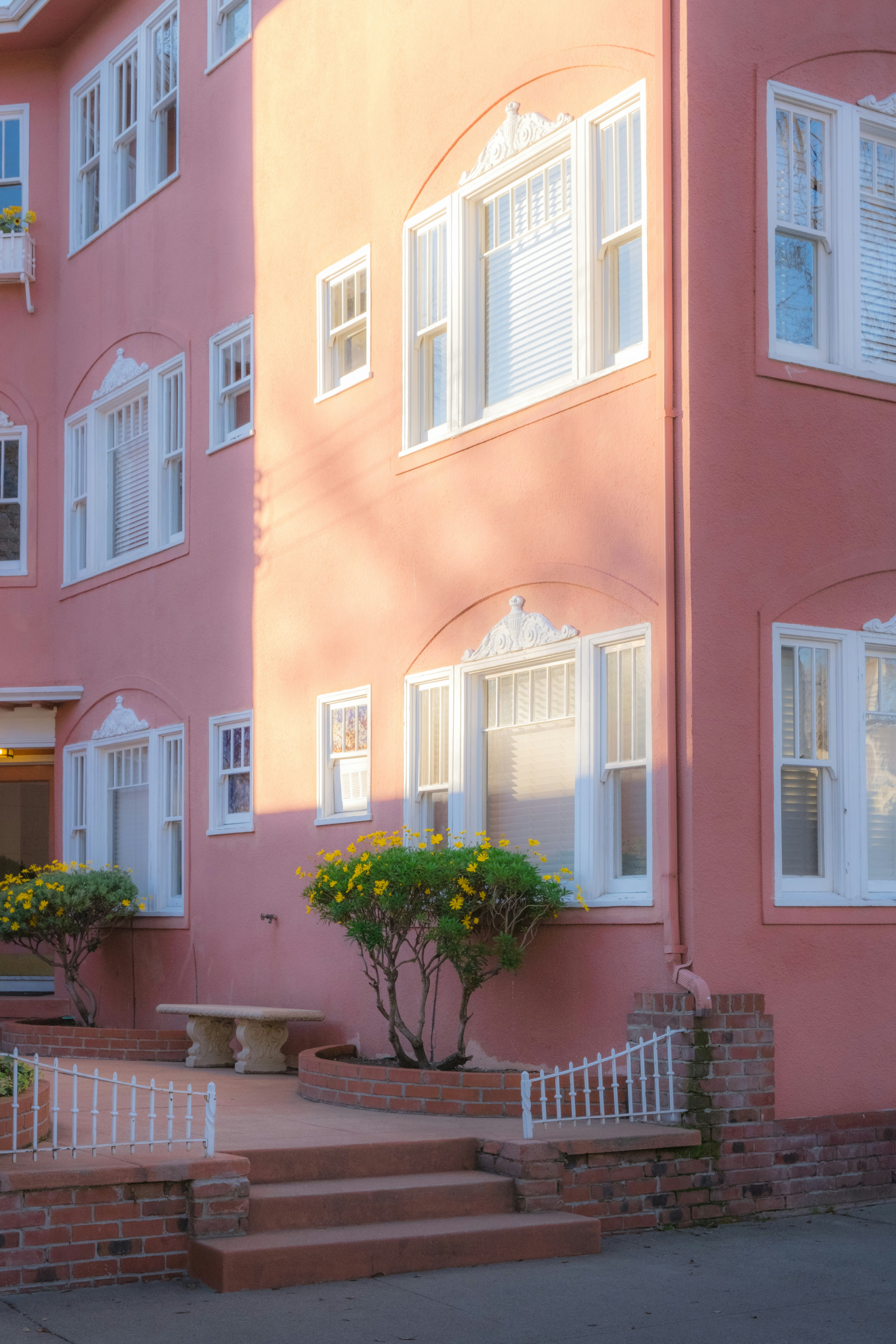 Sunlit Peach Facade: Floral Entryway of a Courtyard Building
