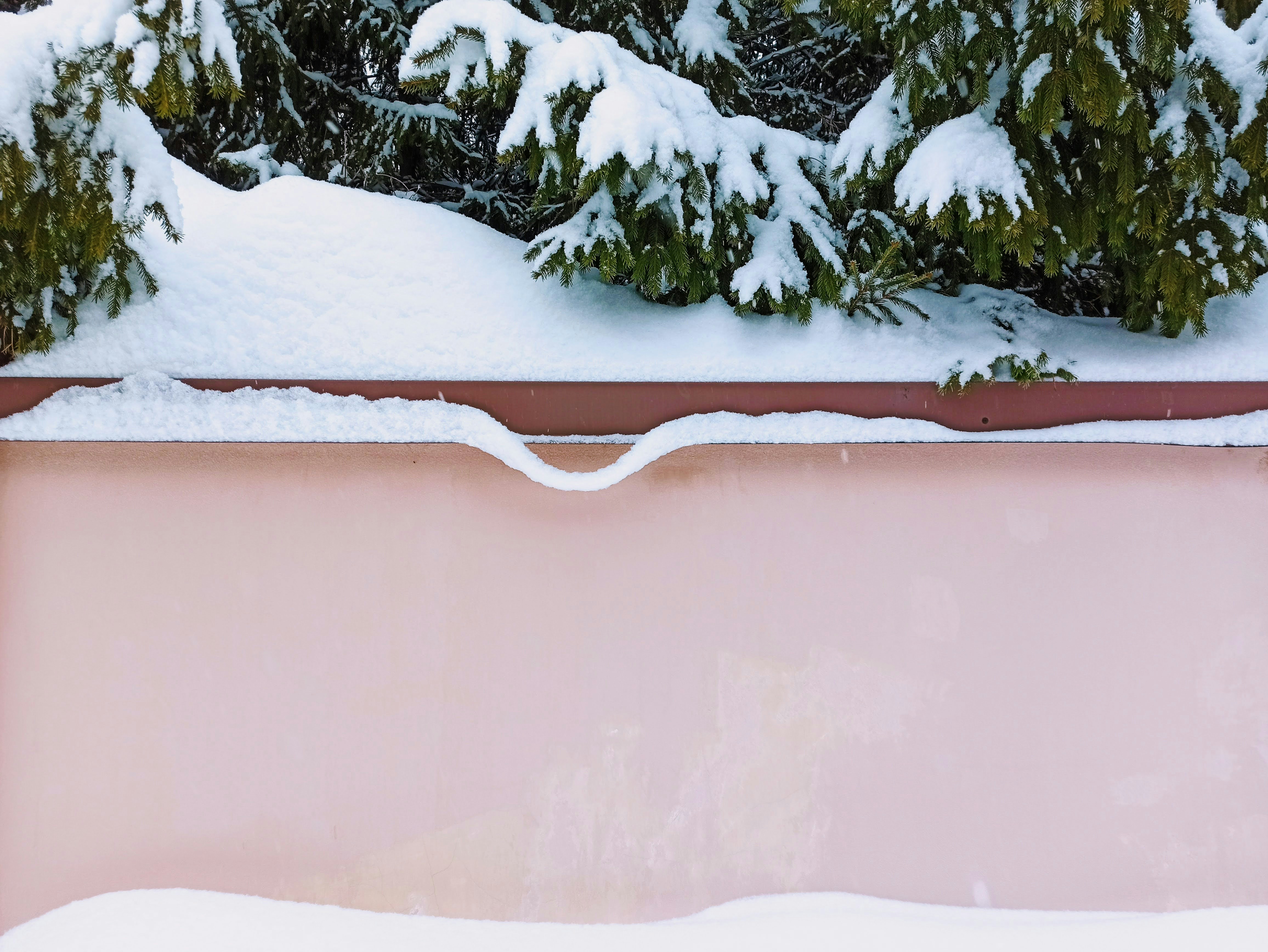 Snow-Capped Roofline Echoing a Soft Pink Wall