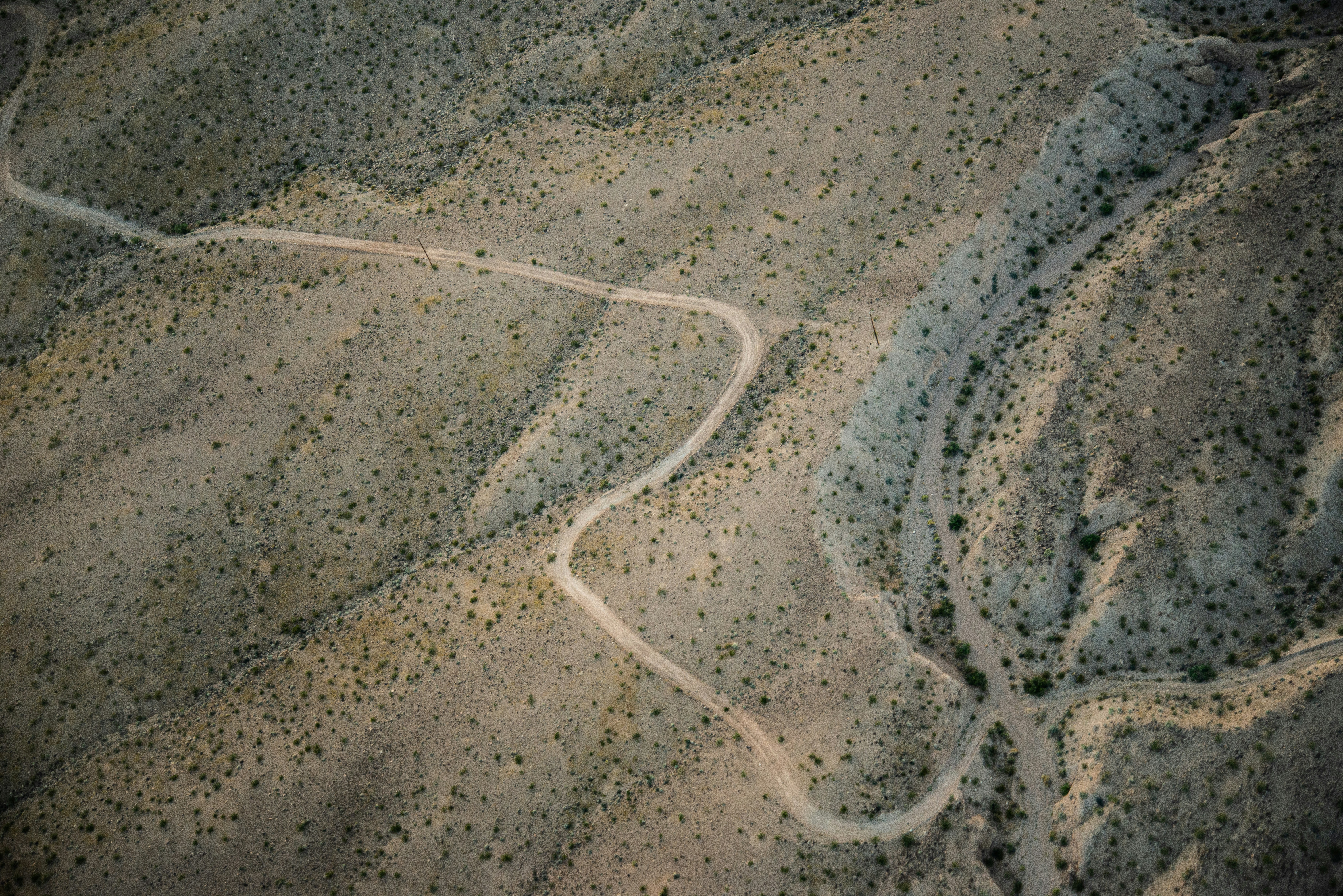 Curving dirt road meanders through a barren landscape, showcasing the stark beauty of the desert environment.