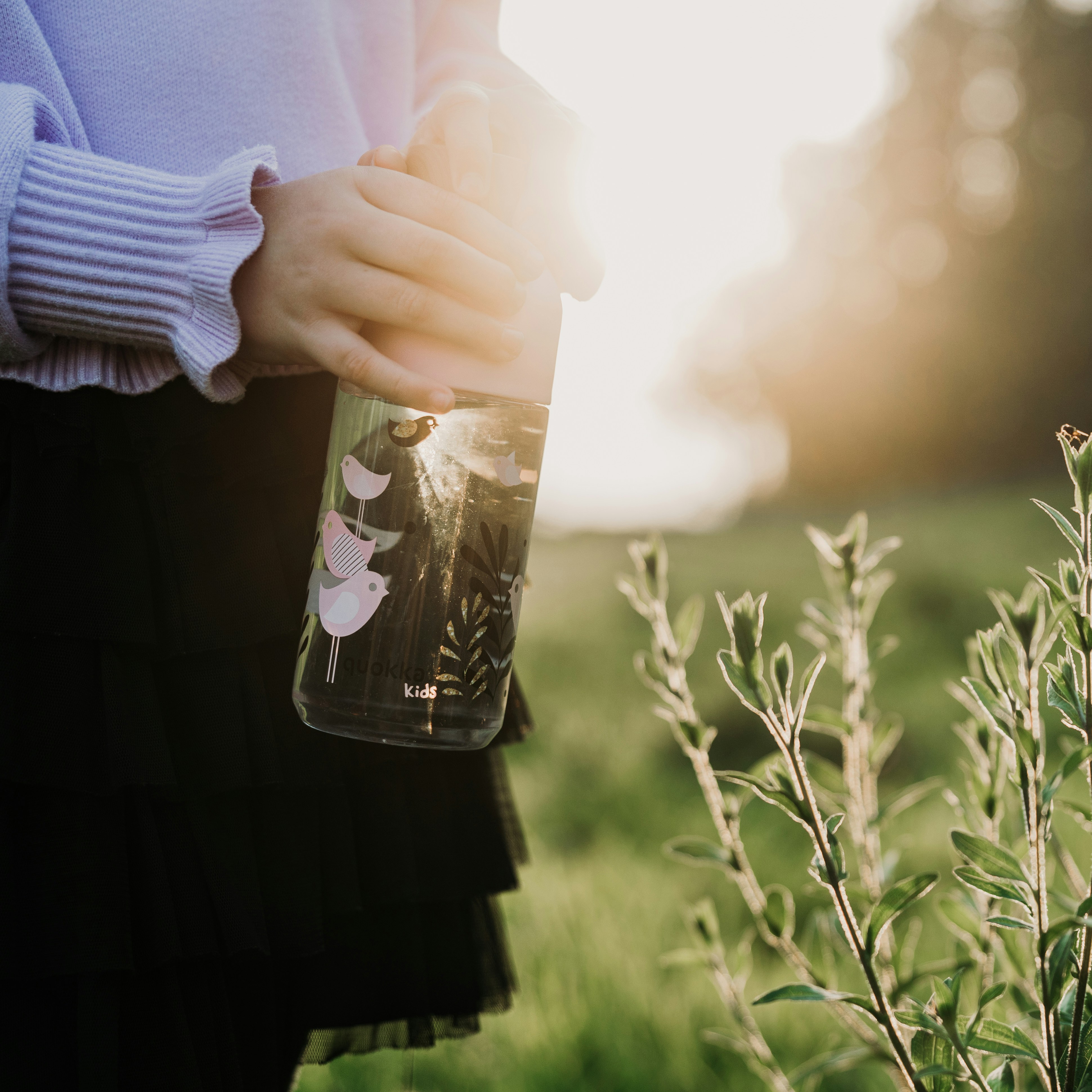 Sunlit Hold: A Floral Bottle in a Backlit Field