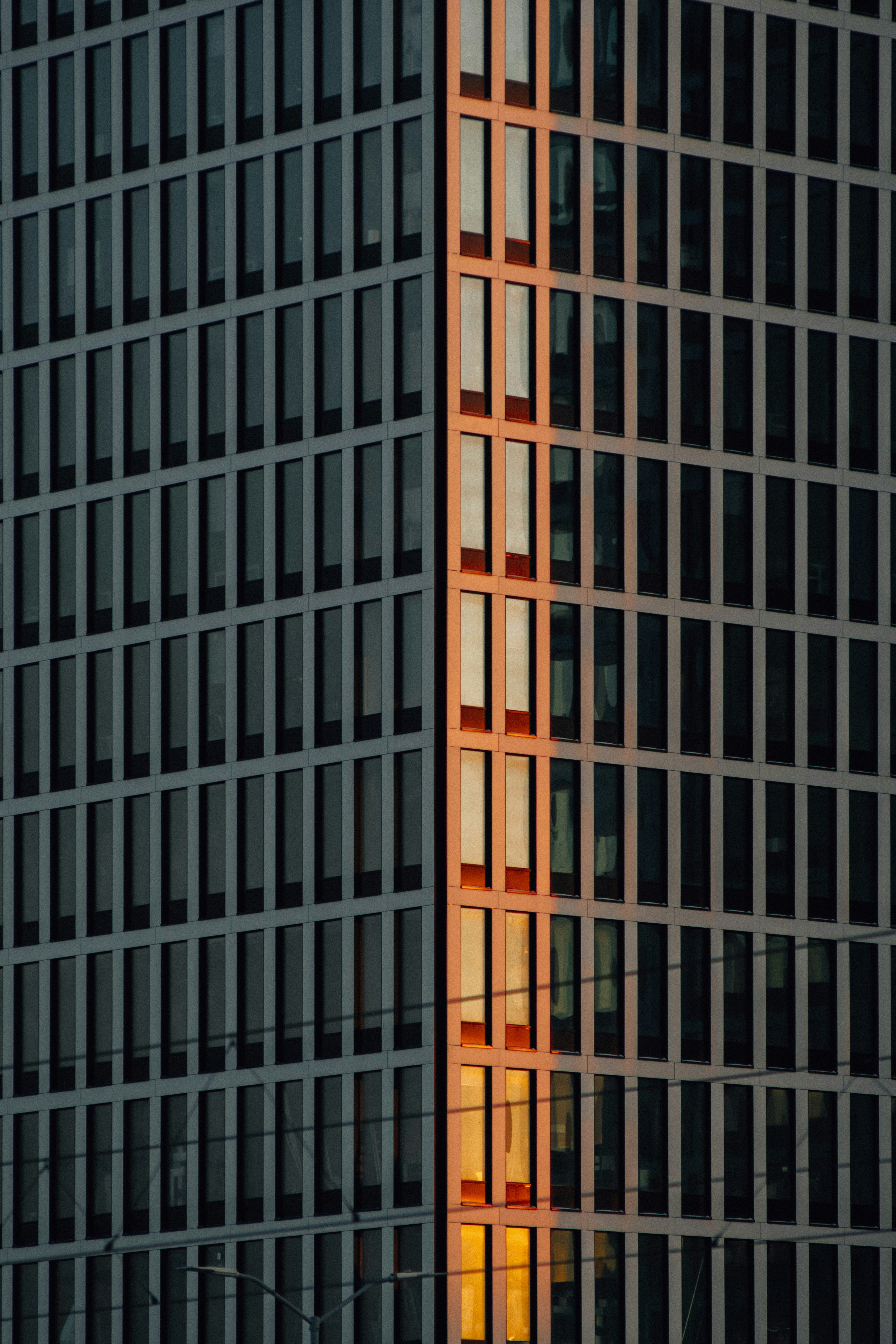 A close-up view of a contemporary skyscraper showcasing intricate patterns of glass and reflections of sunlight. The architectural lines create a striking visual contrast.