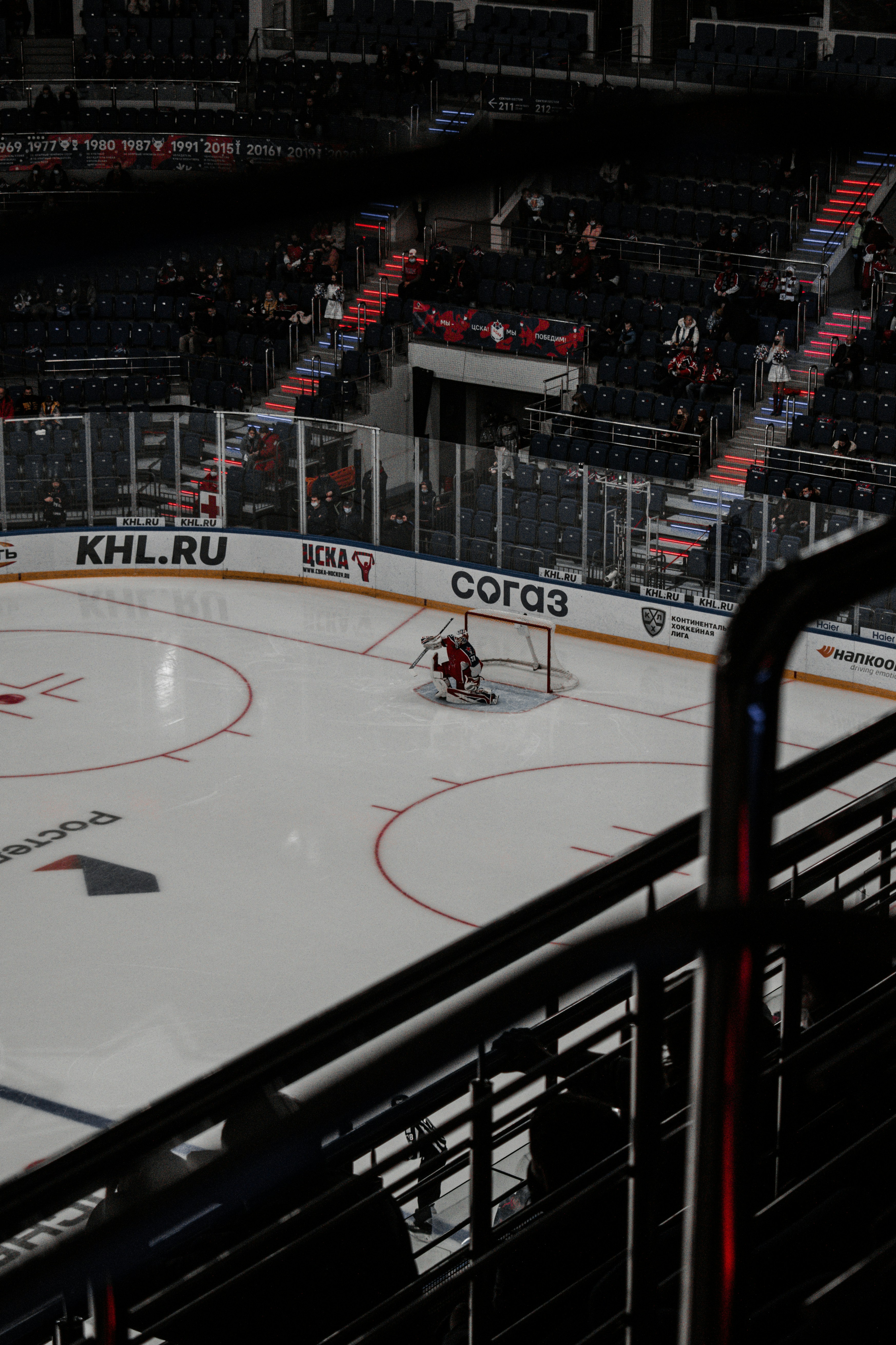 Stilled Moment on Ice: a lone goaltenderGuard amid empty seats