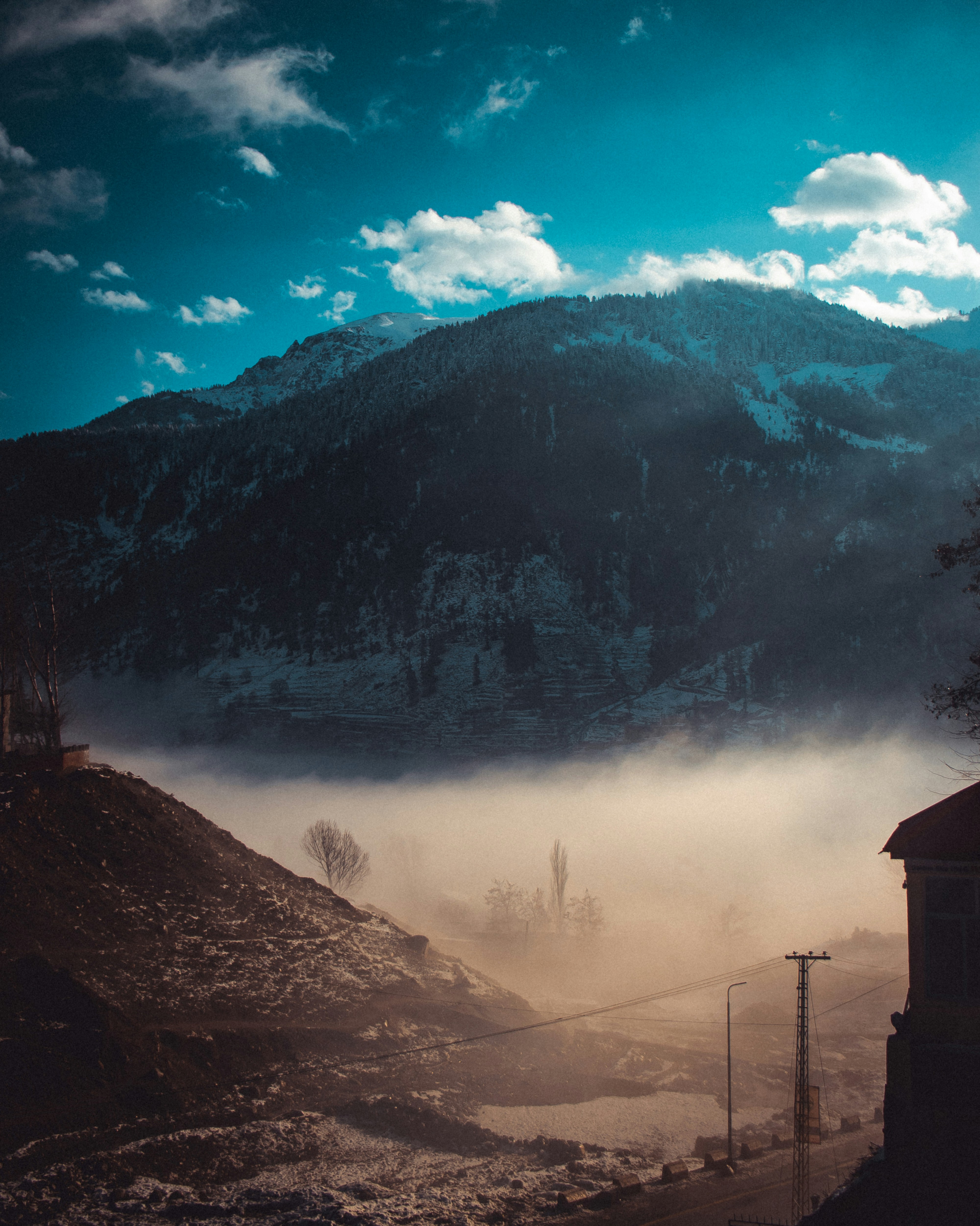 Cyan Sky Over a Mist-Wreathed Valley Between Mountain Ridges