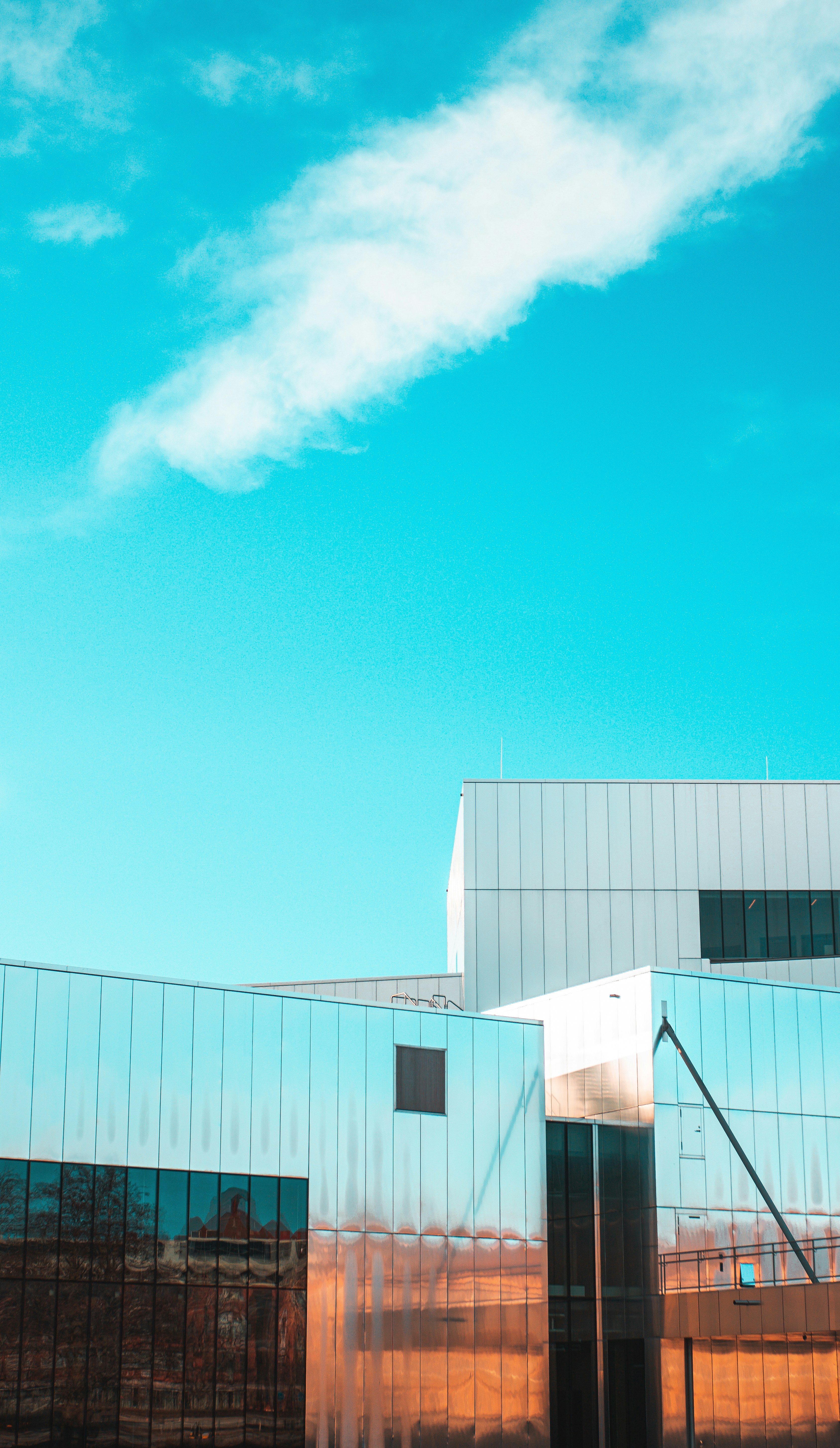 Modern white and blue building with reflective surfaces under a clear blue sky.