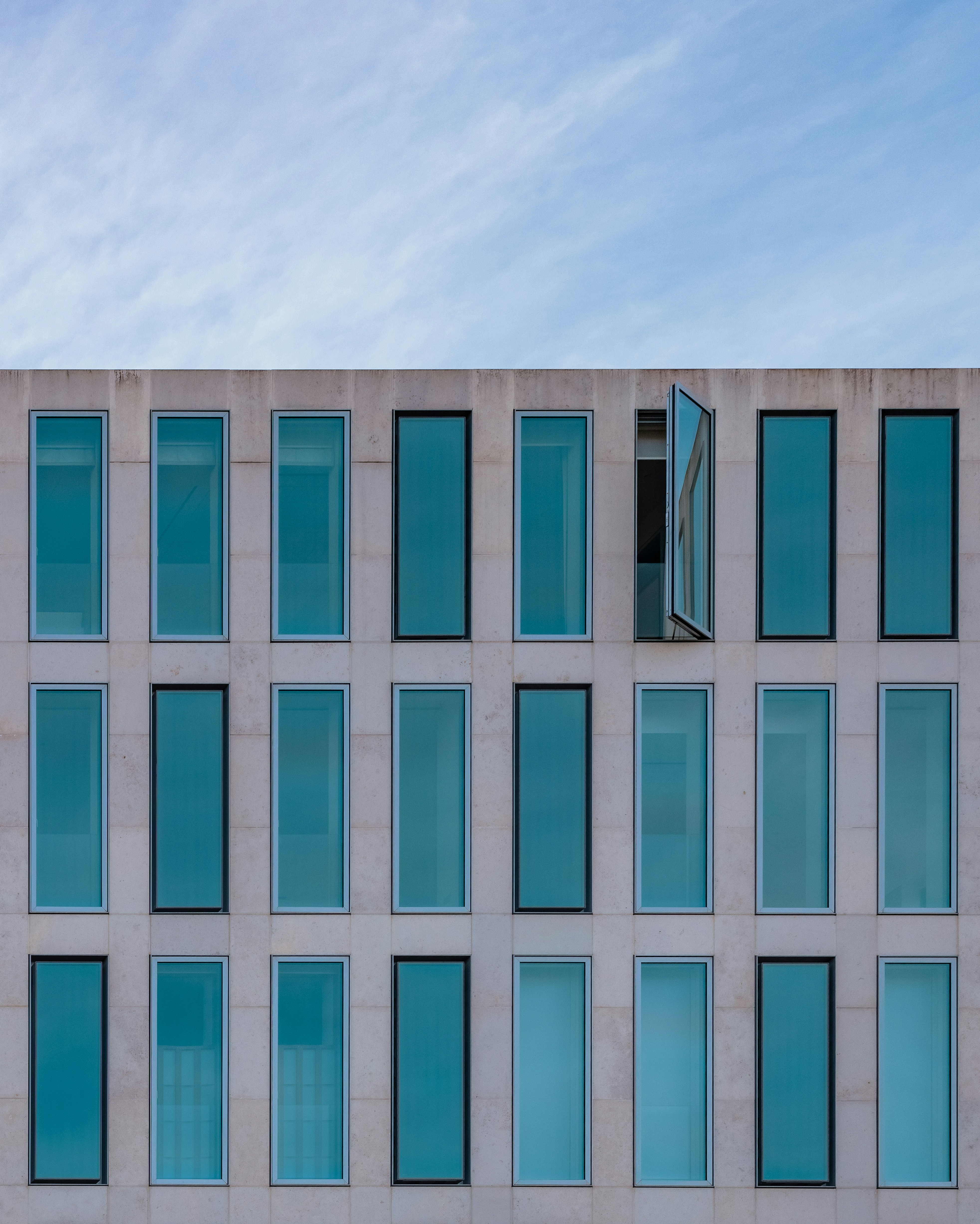 Vertical Window Grid: A Facade of Teal Frames Against Concrete
