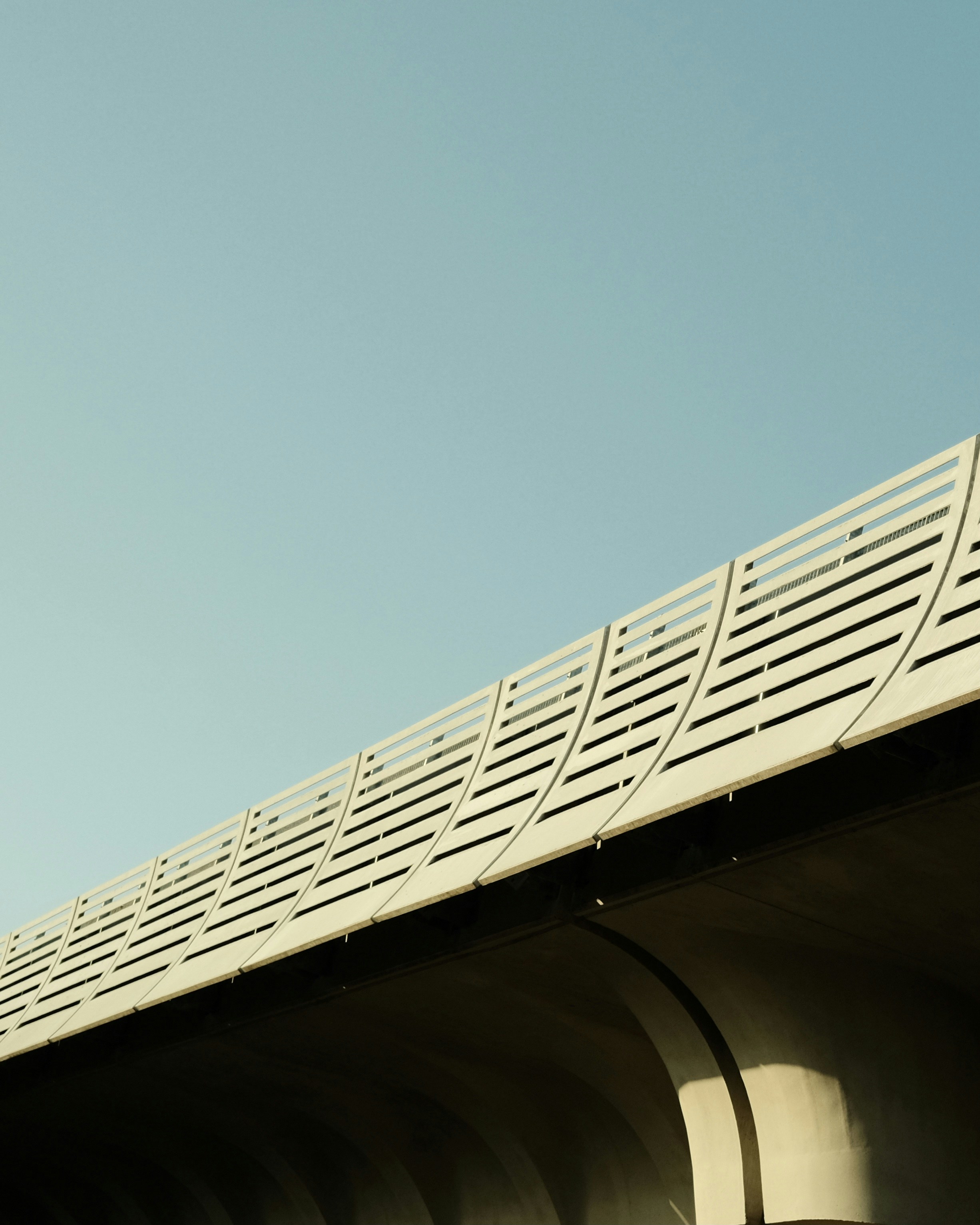 Curved concrete structure contrasting against a clear blue sky, highlighting modern architectural design.