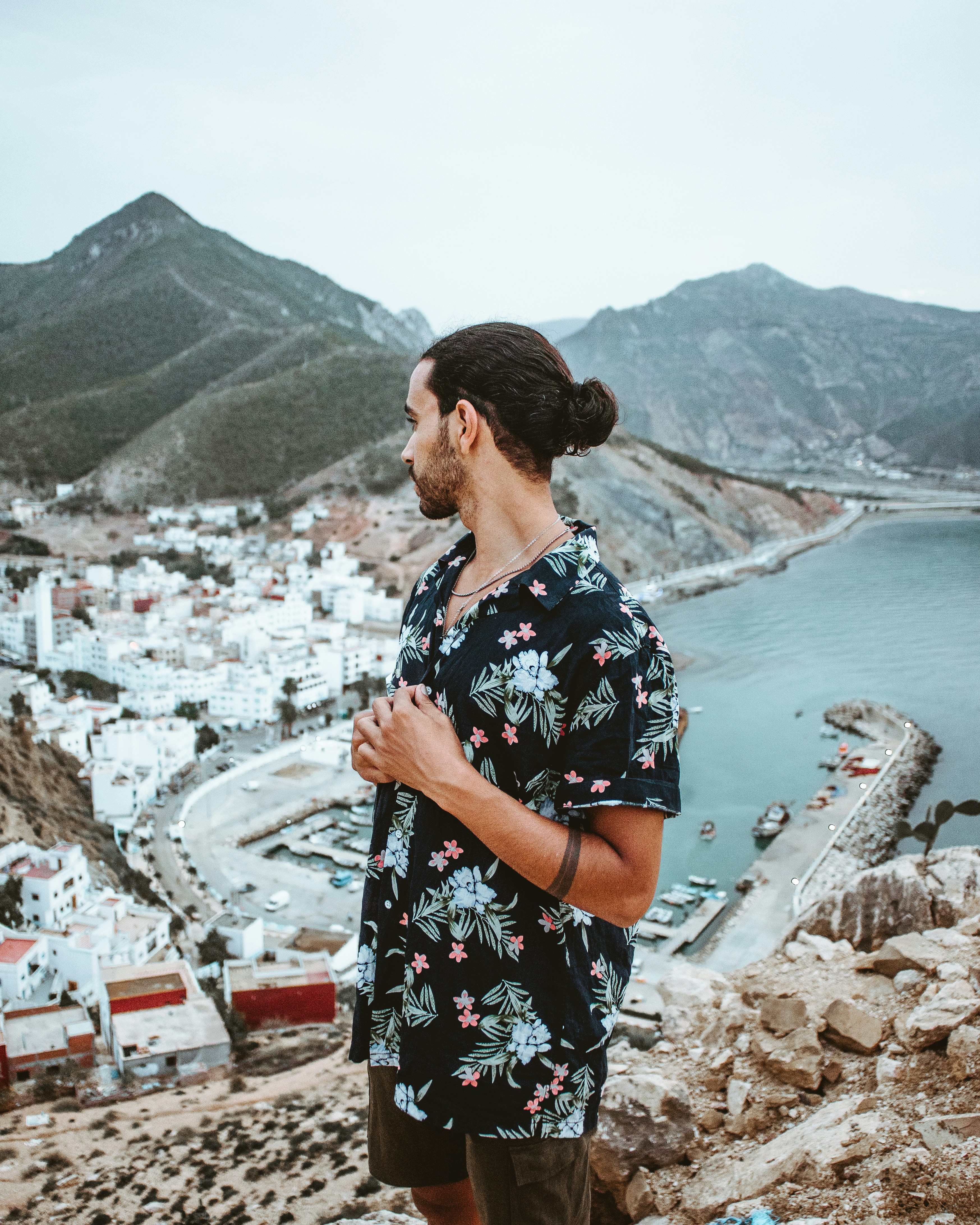 Woman in black and white floral dress standing on rock formation near ...