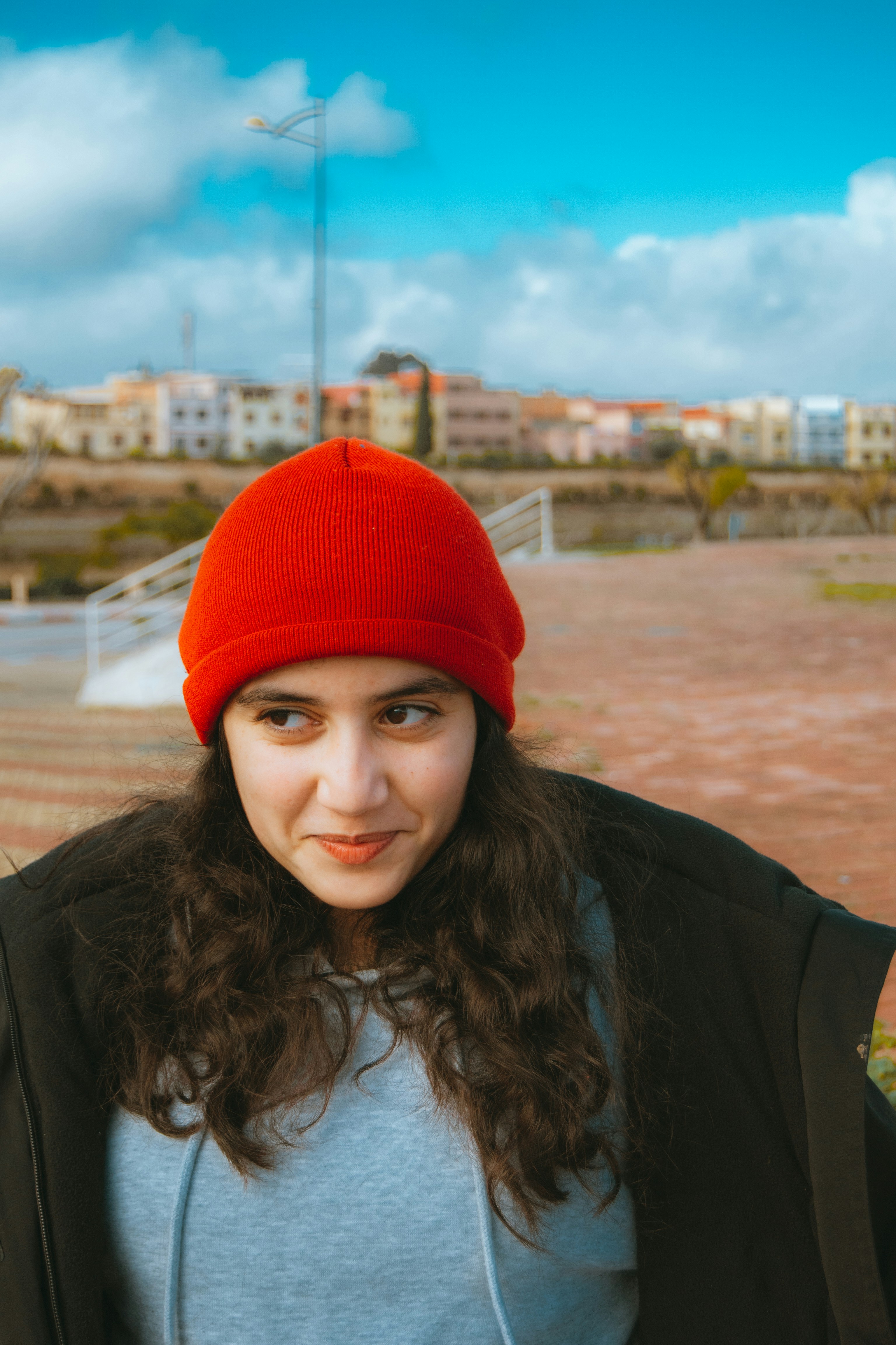Crimson Beanie Portrait by the Seafront Promenade