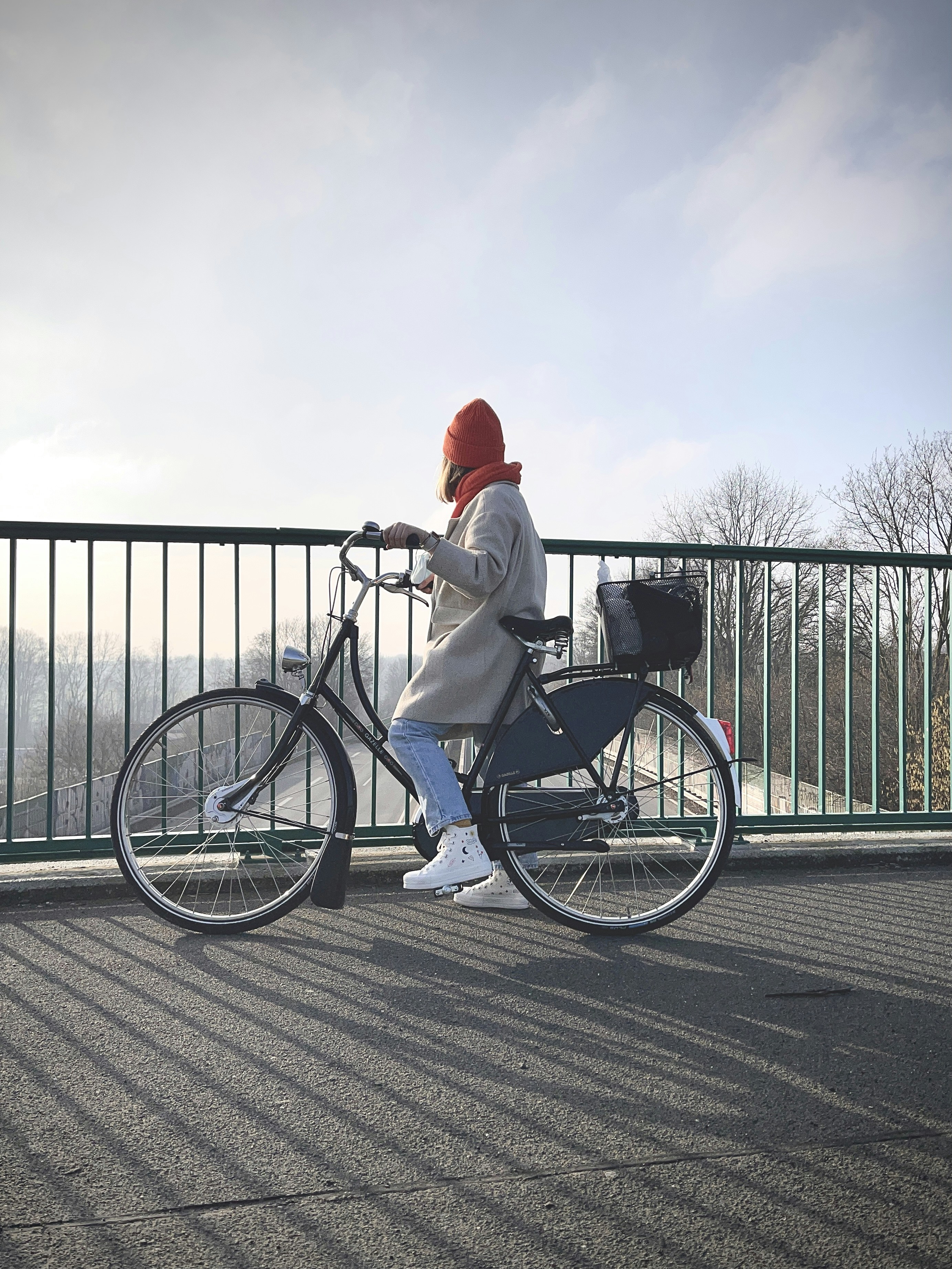 Red Beanie Rider on a Rail-Guarded Bridge in Quiet Winter Light