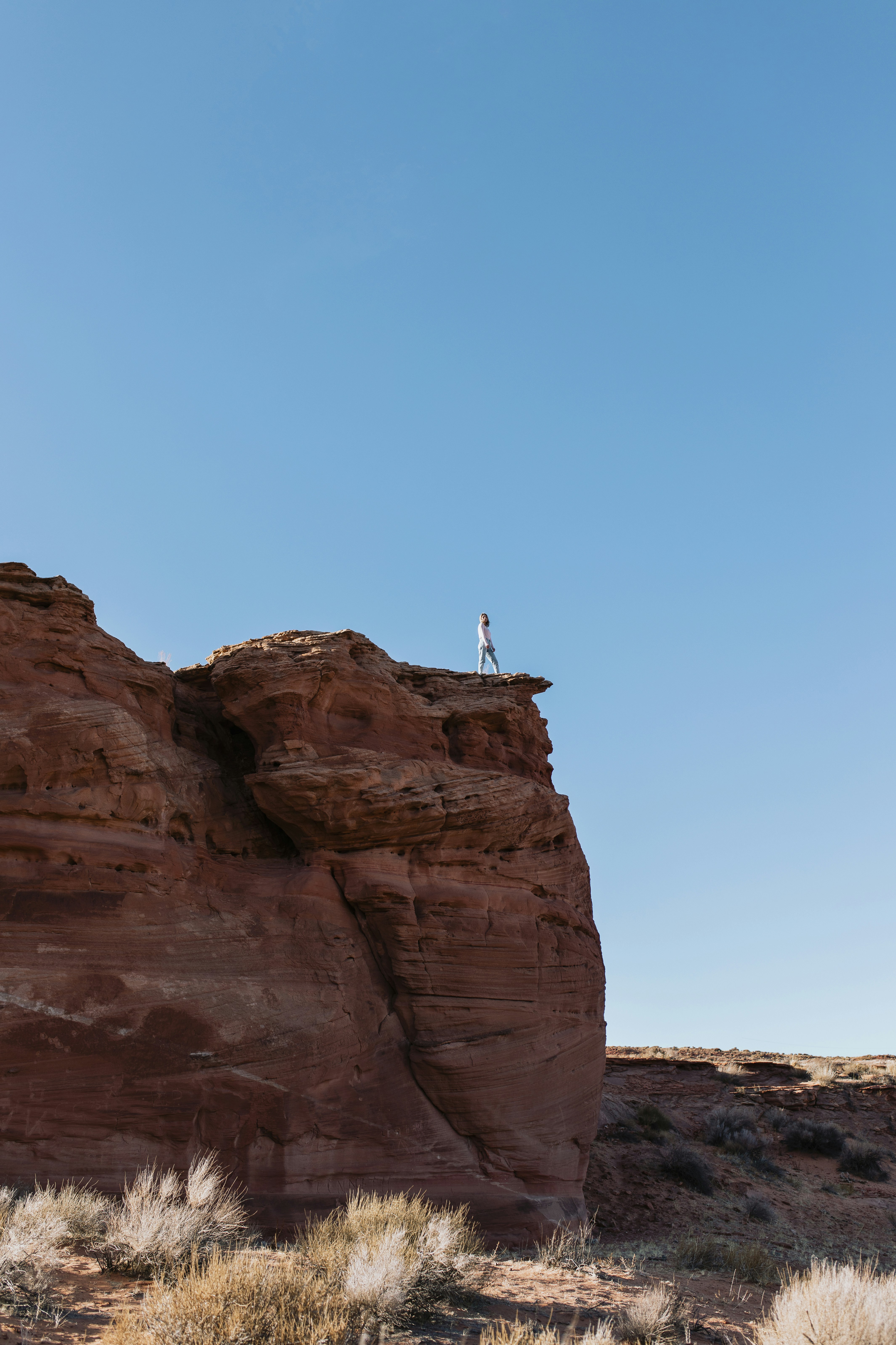 On the Edge of the Red Cliff: A Lone Figure Overlooking the Desert Expanse