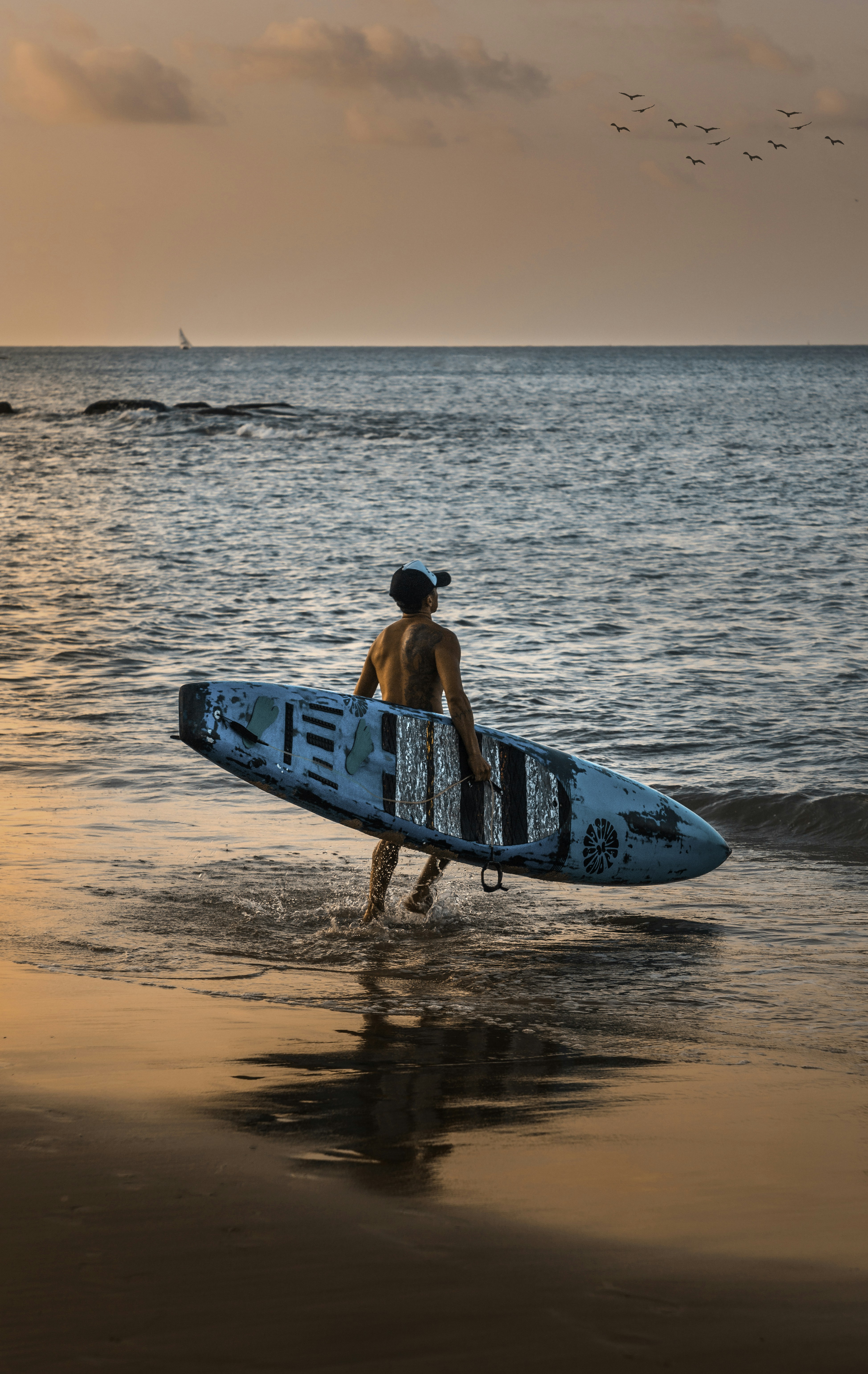 woman in black bikini sitting on blue surfboard on beach during daytime