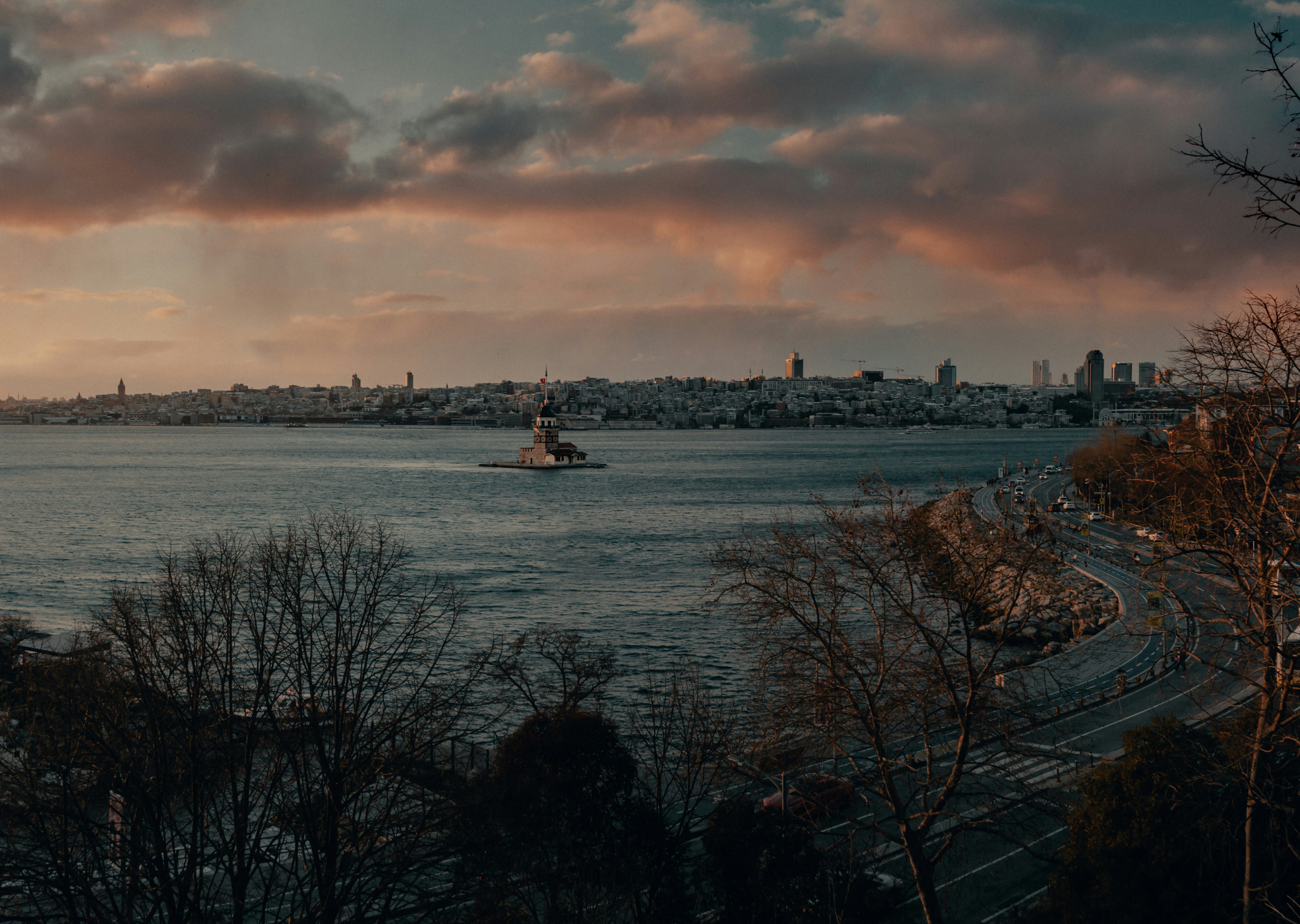 Copper Sunset over a Quiet Harbor: A Tug Traces the River Beneath a City Skyline