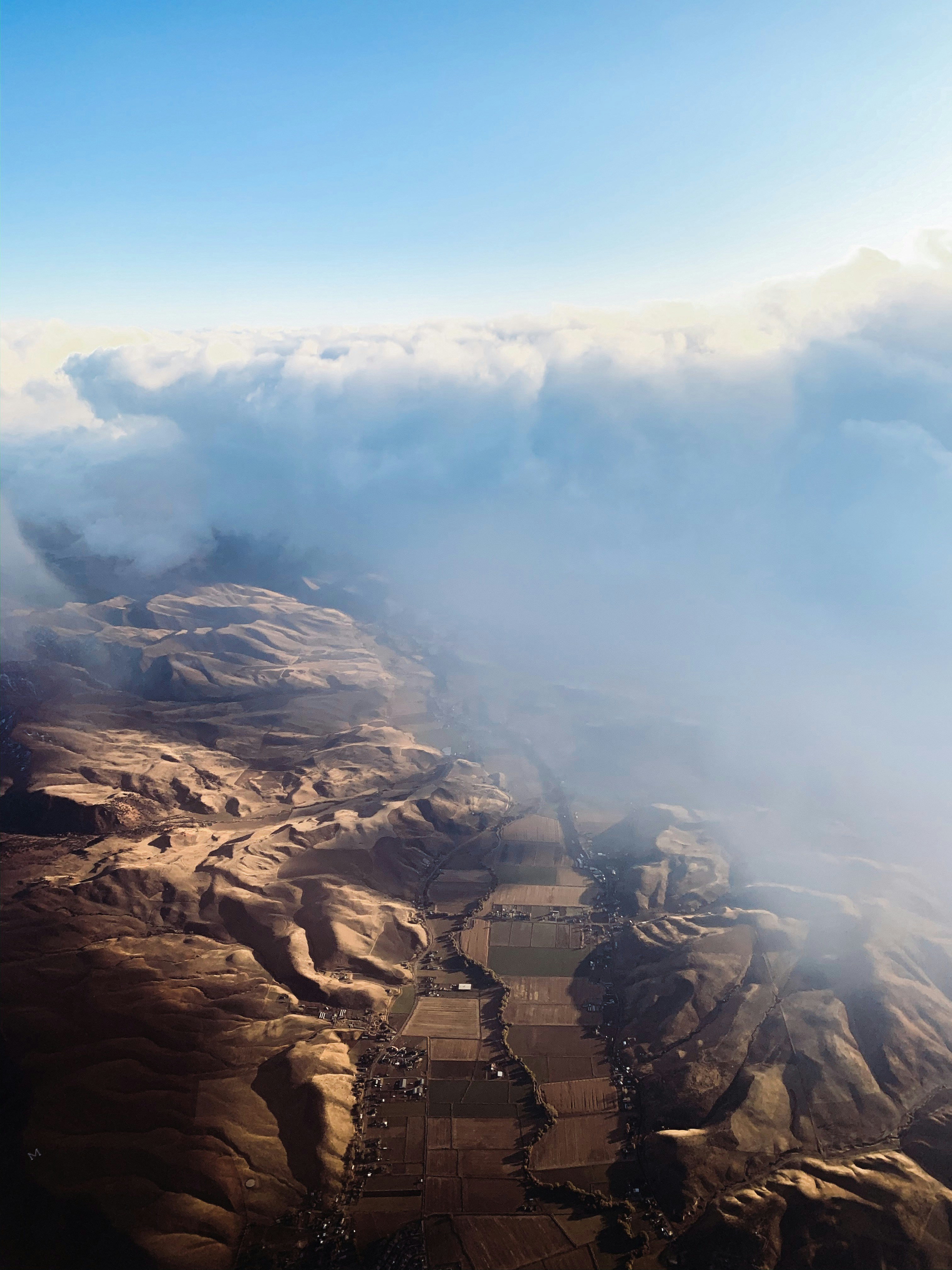 Terraced Desert: Aerial Quilt of Valleys and Fields Beneath a Cloud-Swept Sky