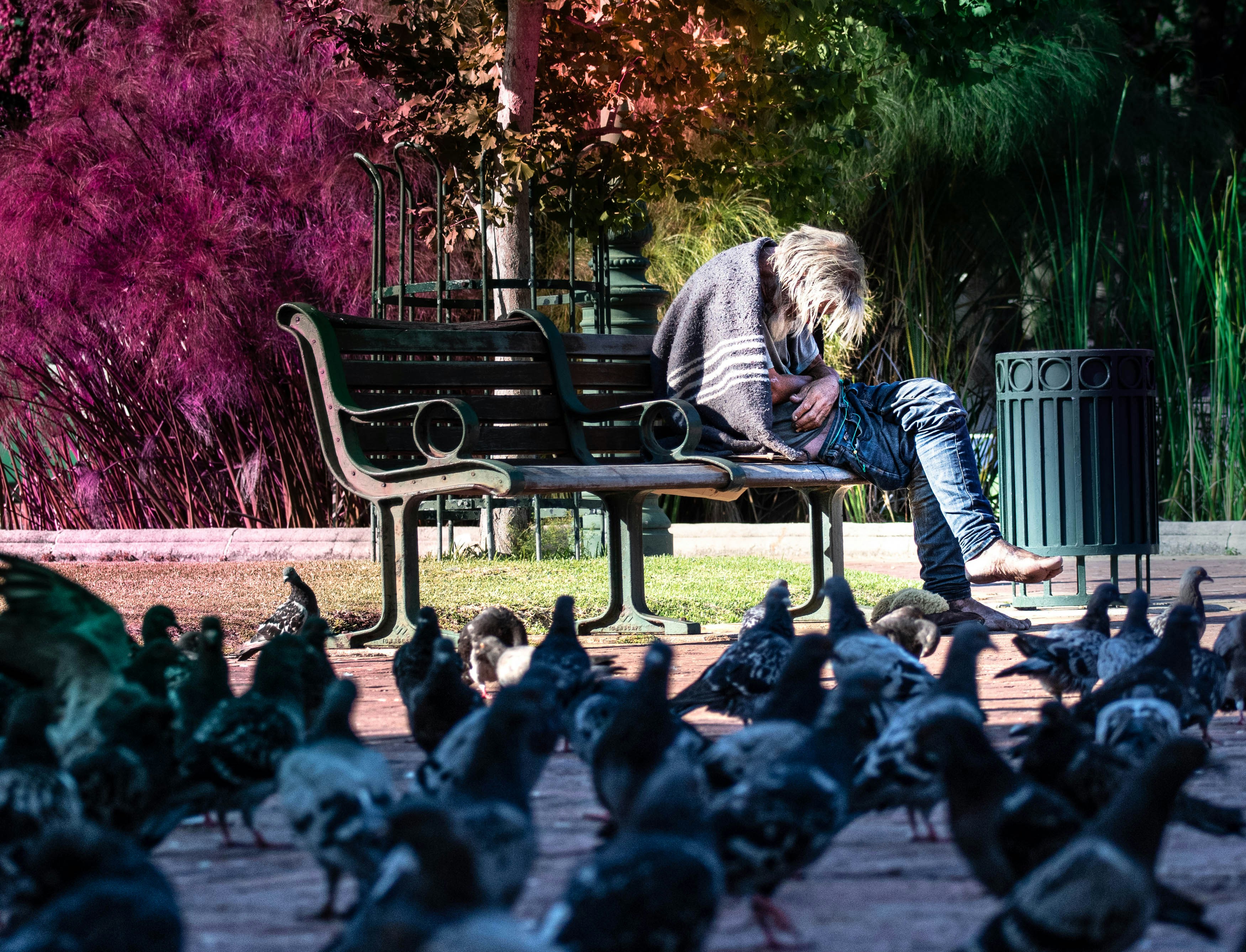 Man in blue and white striped long sleeve shirt sitting on bench with ...
