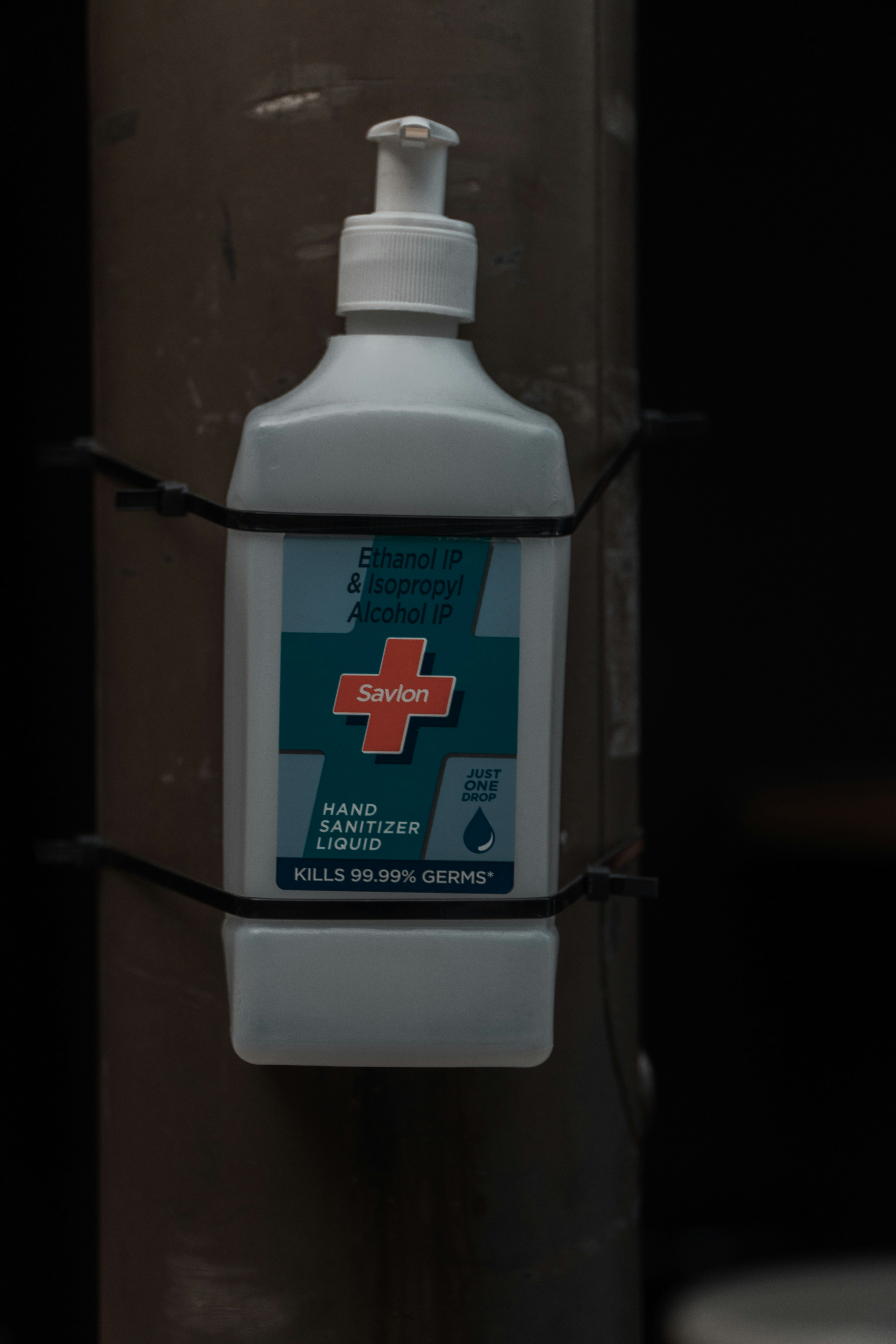 Savlon hand sanitizer bottle secured on a pole, highlighting its key ingredients and effectiveness against germs.
