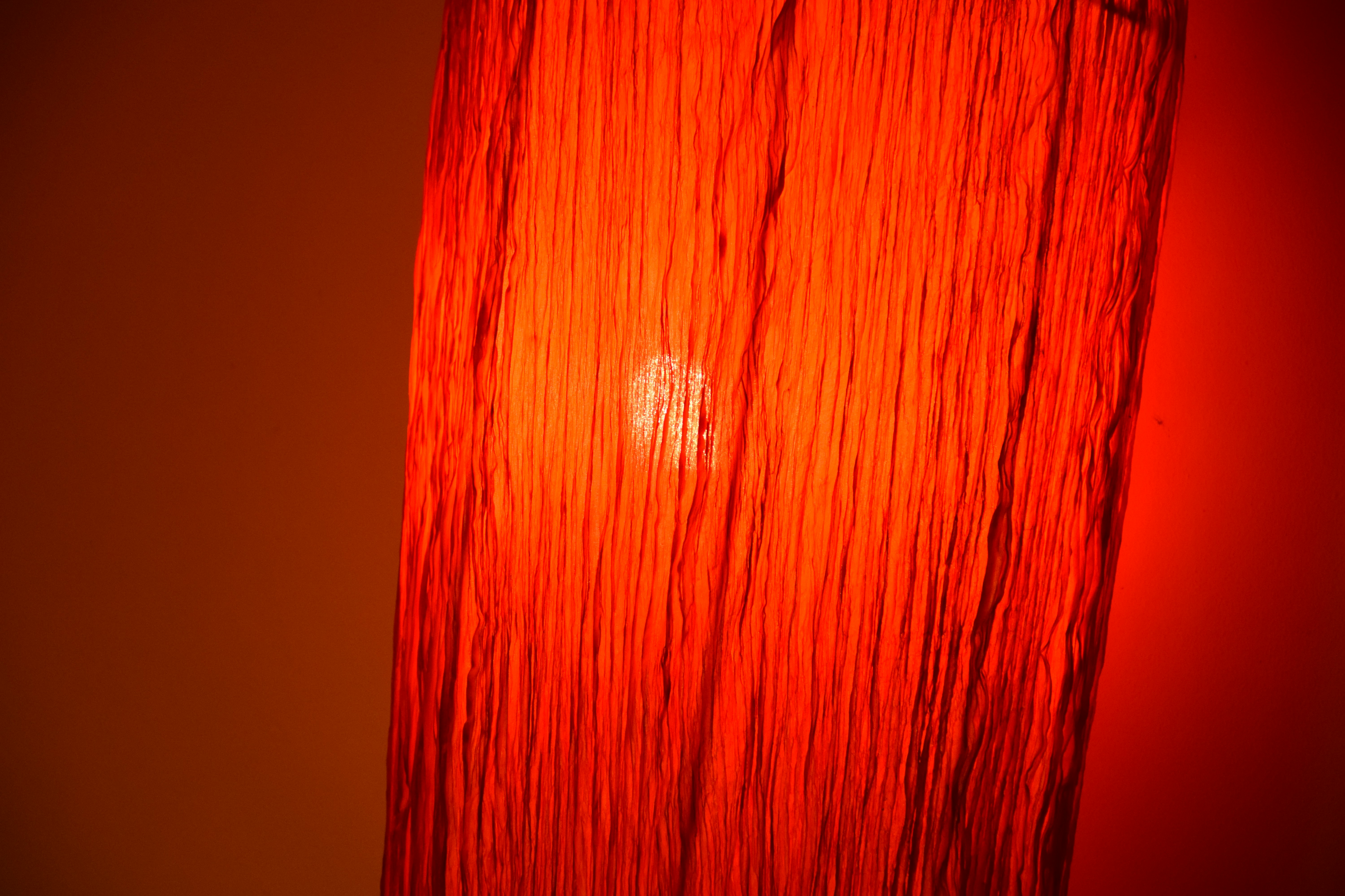 Translucent red fabric softly diffusing light from a hidden source, creating a warm and inviting atmosphere.