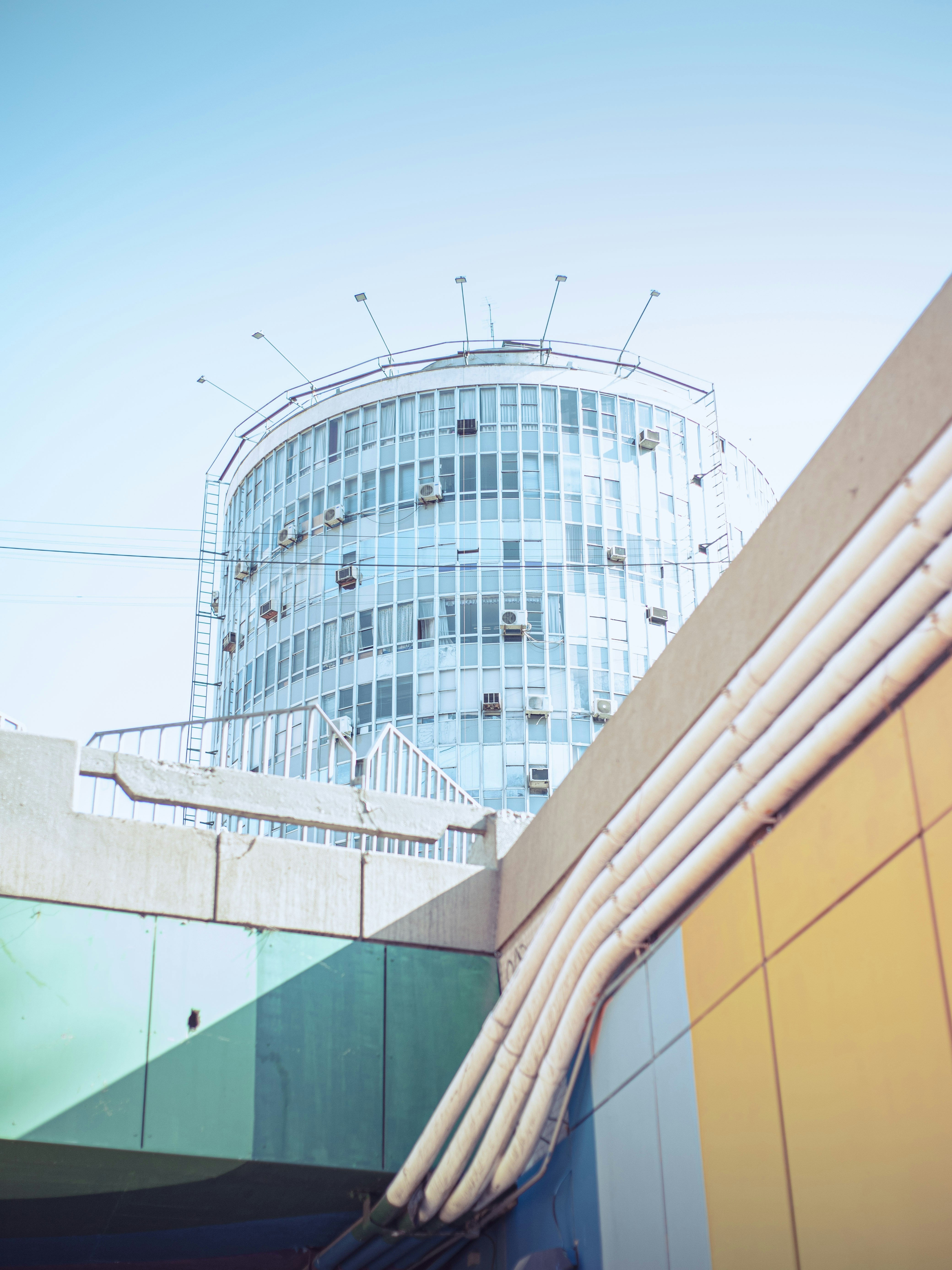 Cylindrical Glass Tower Rising Above a Prism of Urban Panels