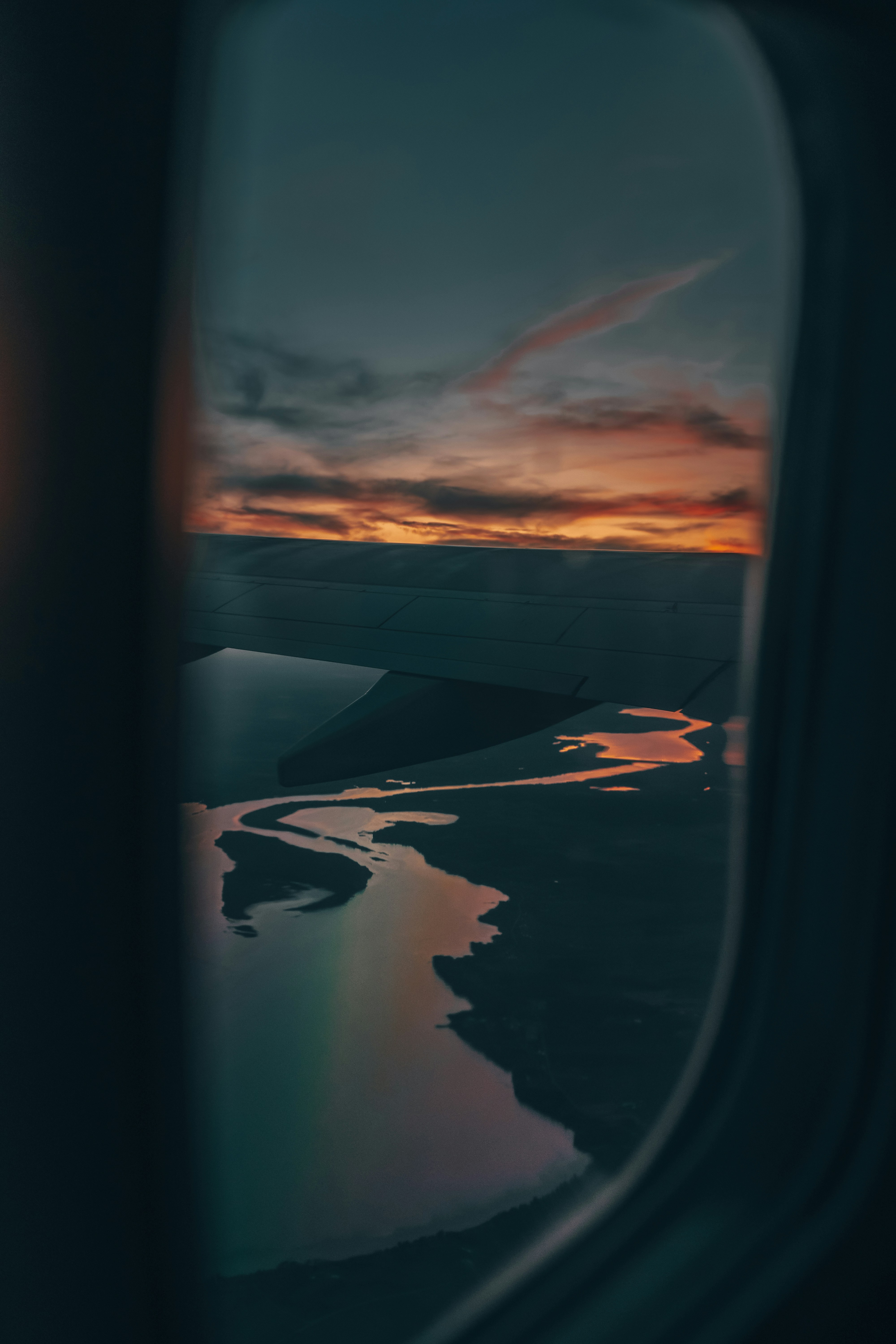 Twilight Wing over Quiet Waters: Sunset Reflections Through a Plane Window